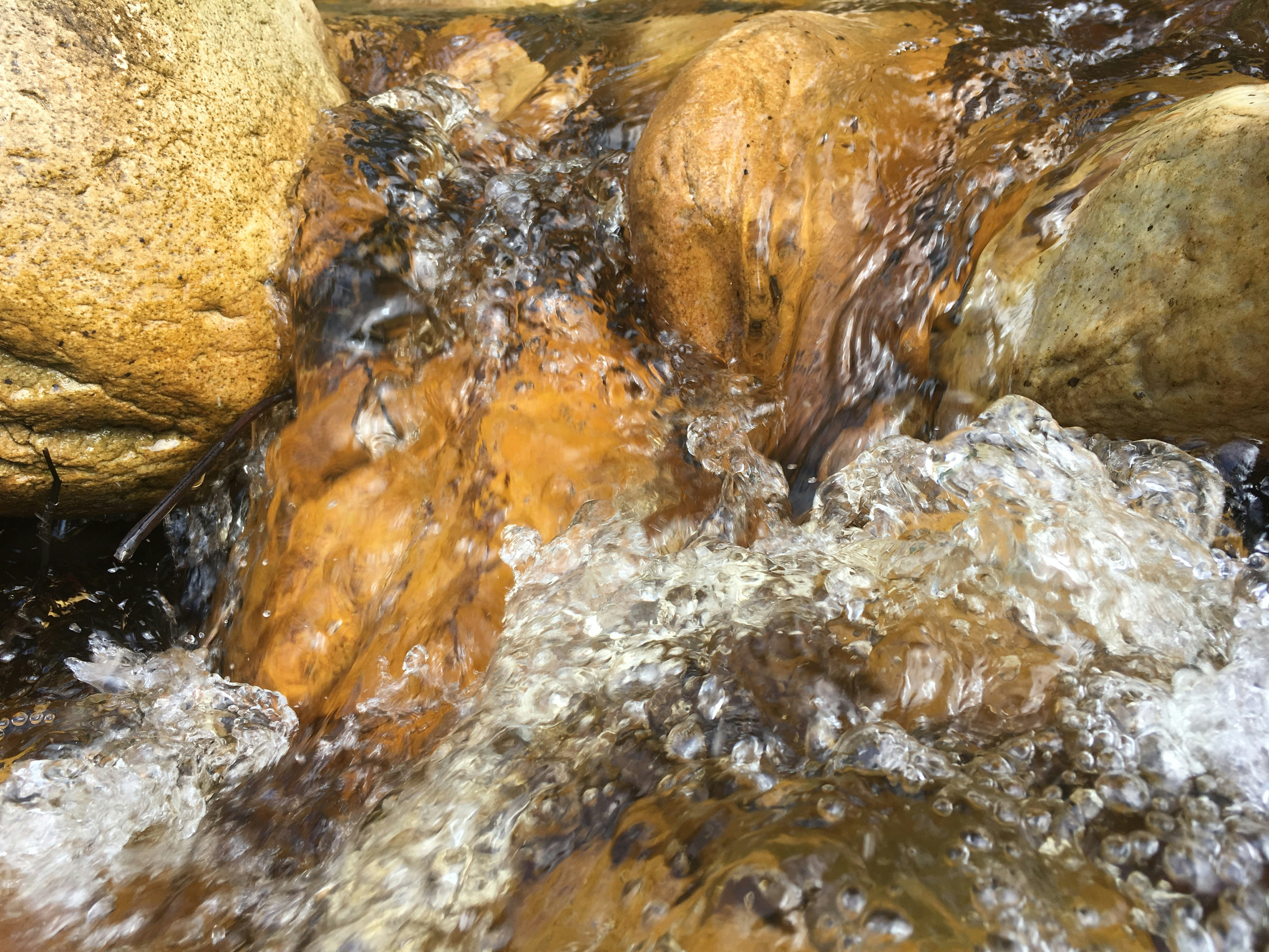 Ember Cascade: a sunlit brook among rust-colored stones