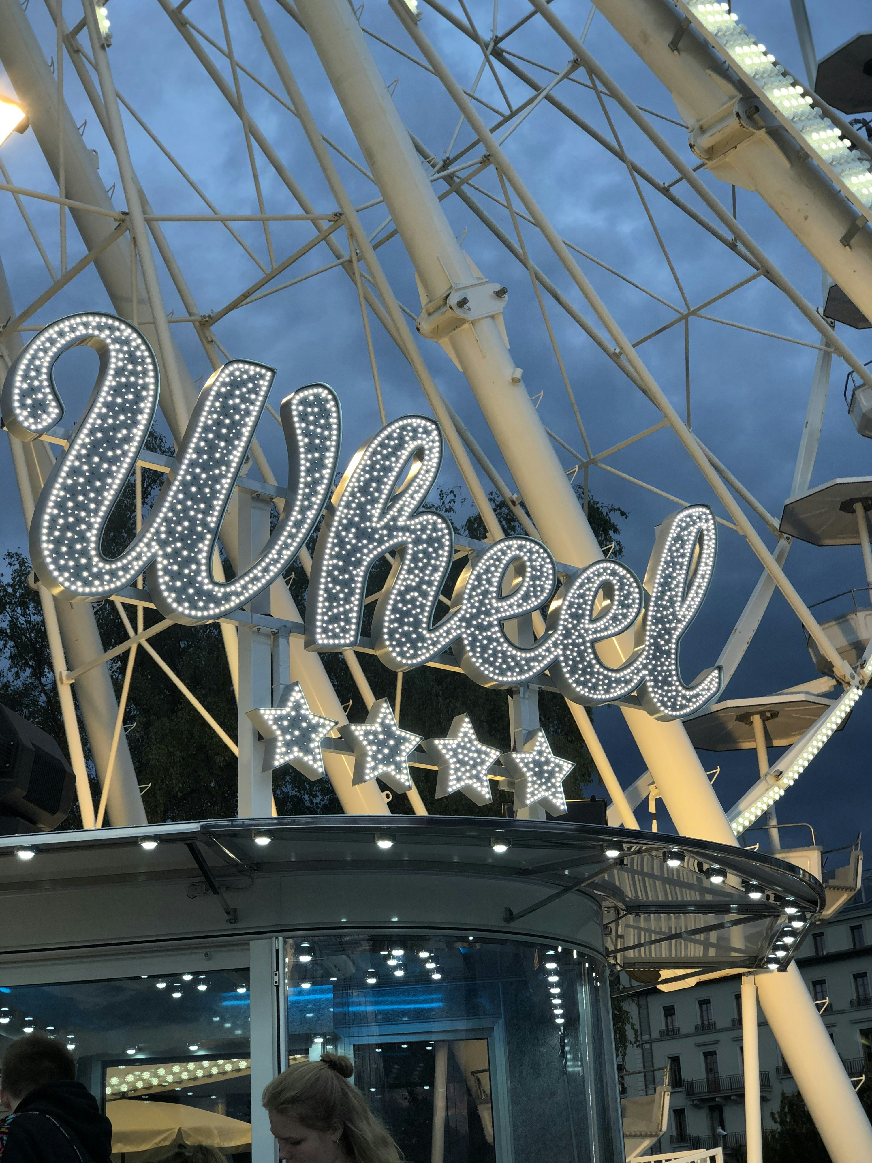 Illuminated 'Wheel' Sign Framed by a Lattice of Steel Arches at Dusk