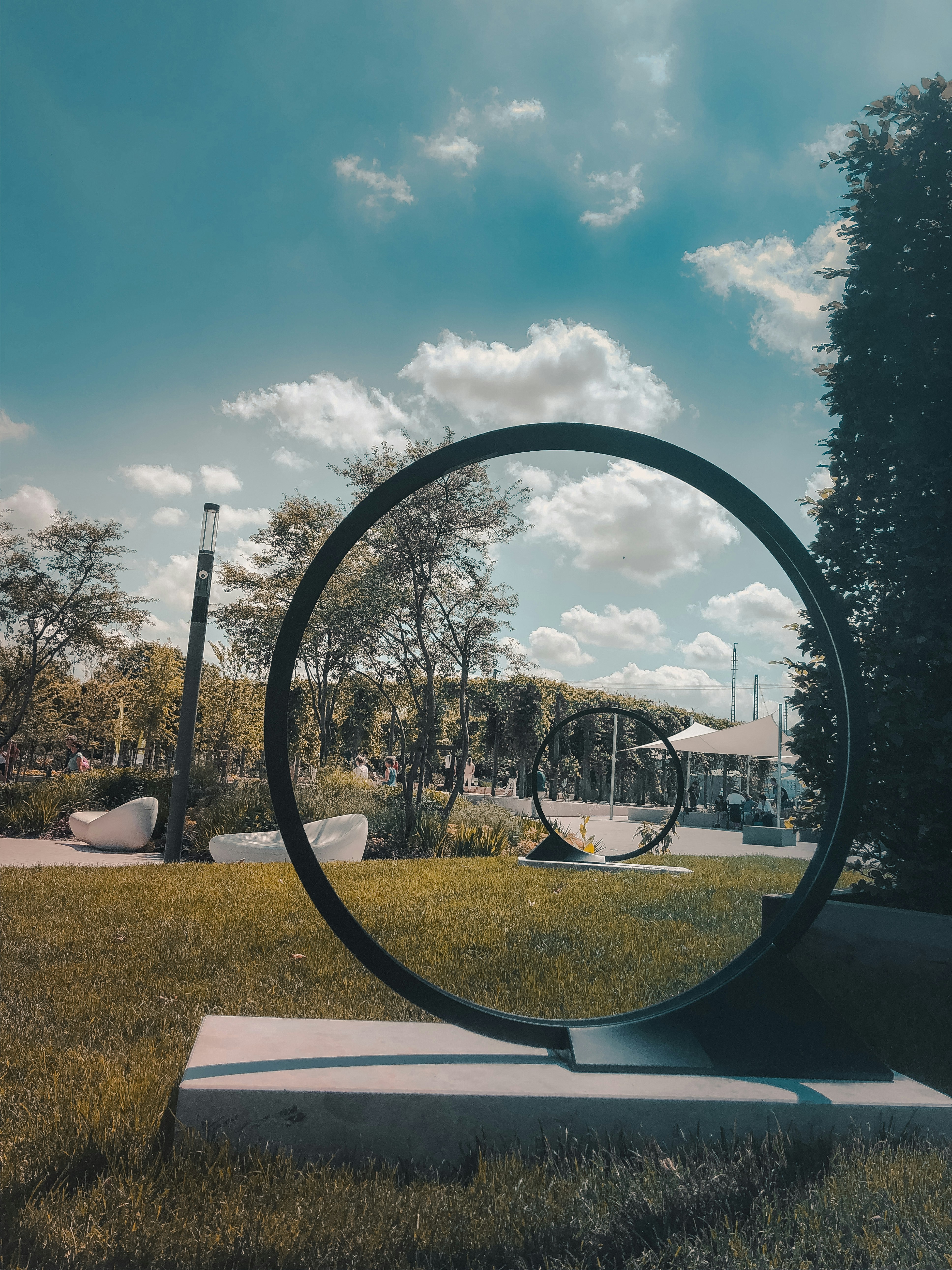 A series of circular sculptures framed by lush greenery and a vibrant sky, creating a harmonious blend of nature and art.