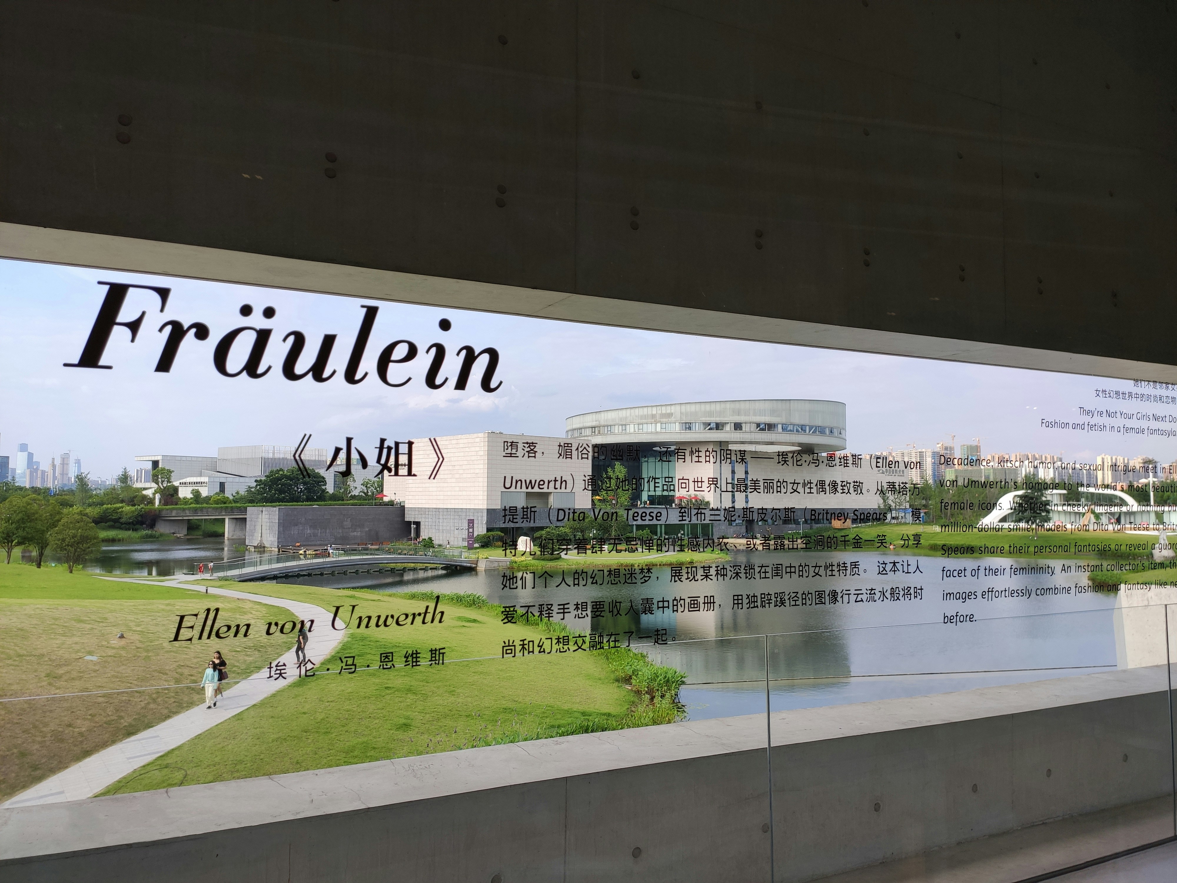 Exhibition banner featuring the title 'Fräulein' with a serene landscape and modern architecture in the background. The scene captures the harmony between art and nature.