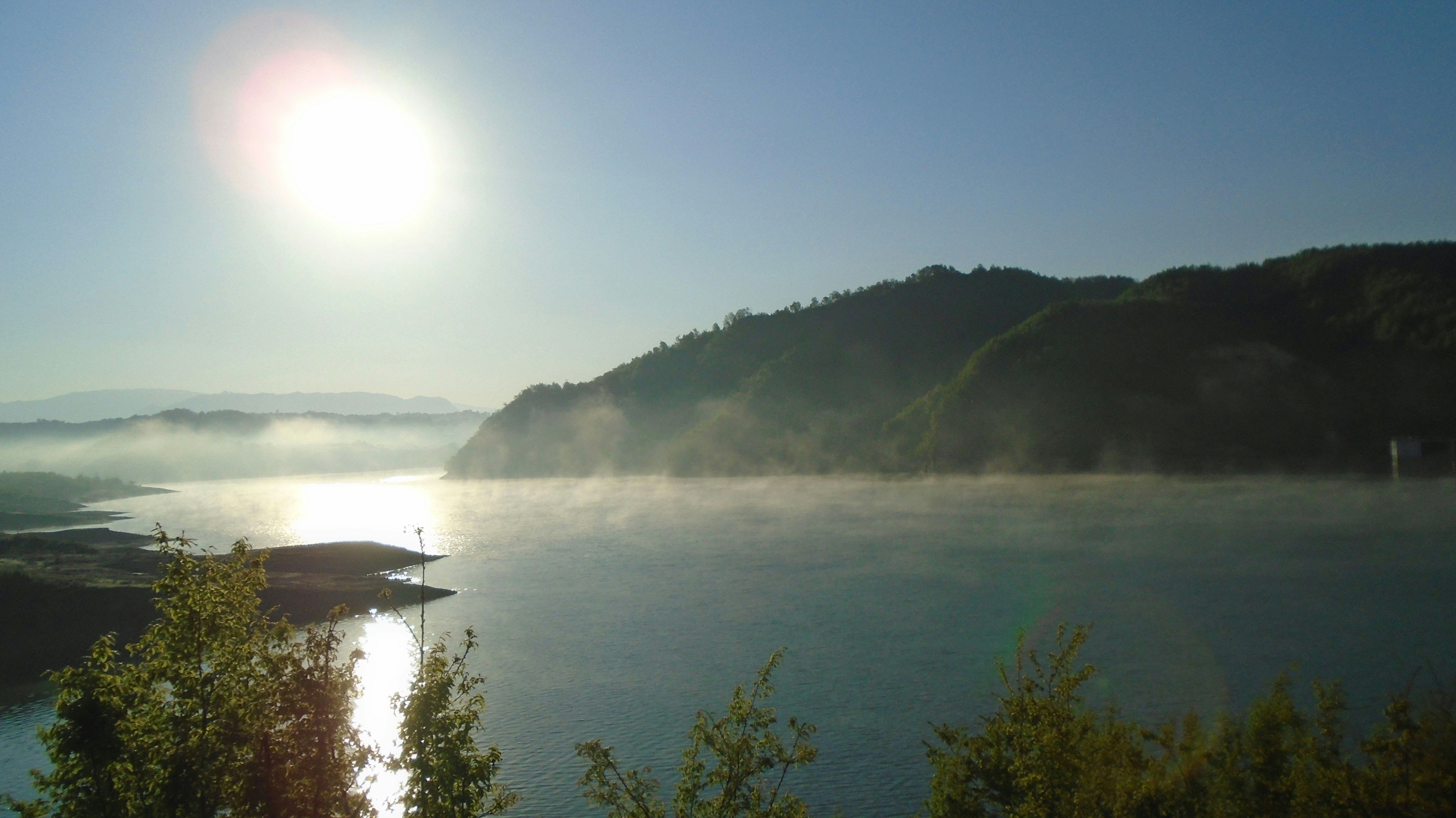 Dawn Mist Skims a Quiet Lake Fringed by Forested Hills
