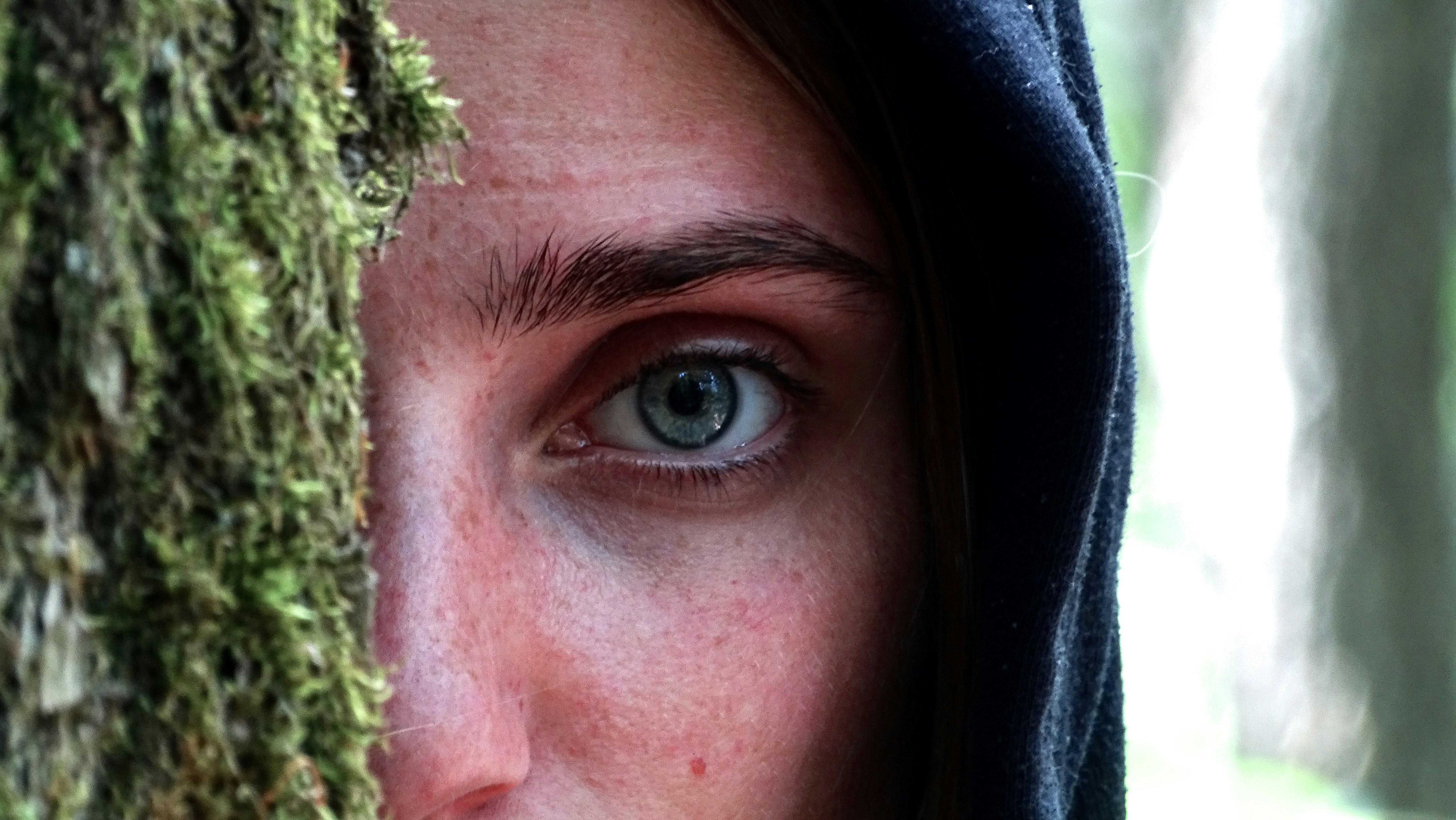 Emerald Gaze Between Moss and Hoodie in a Quiet Forest