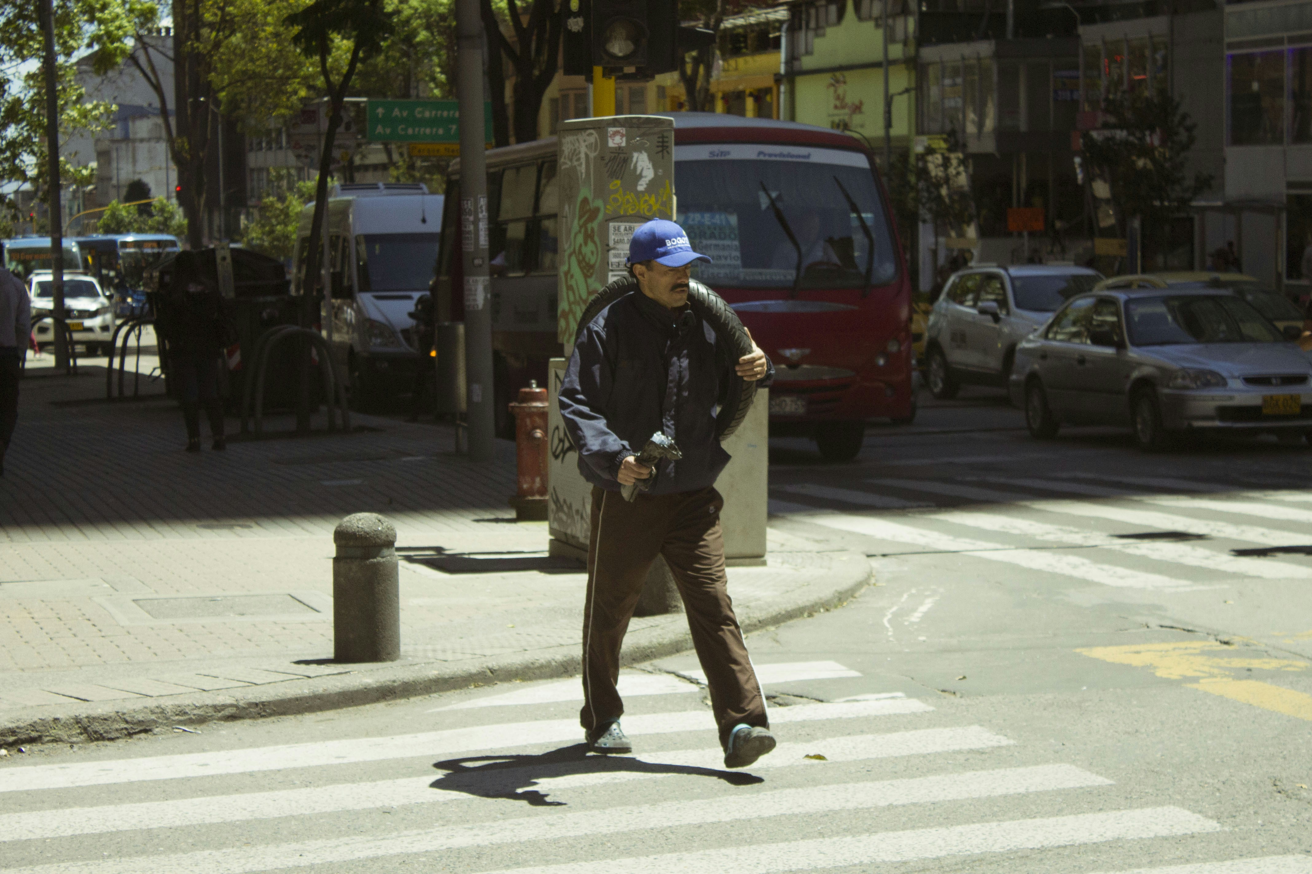 Man carrying motorcycle tire crossing the pedestrian lane photo – Free ...