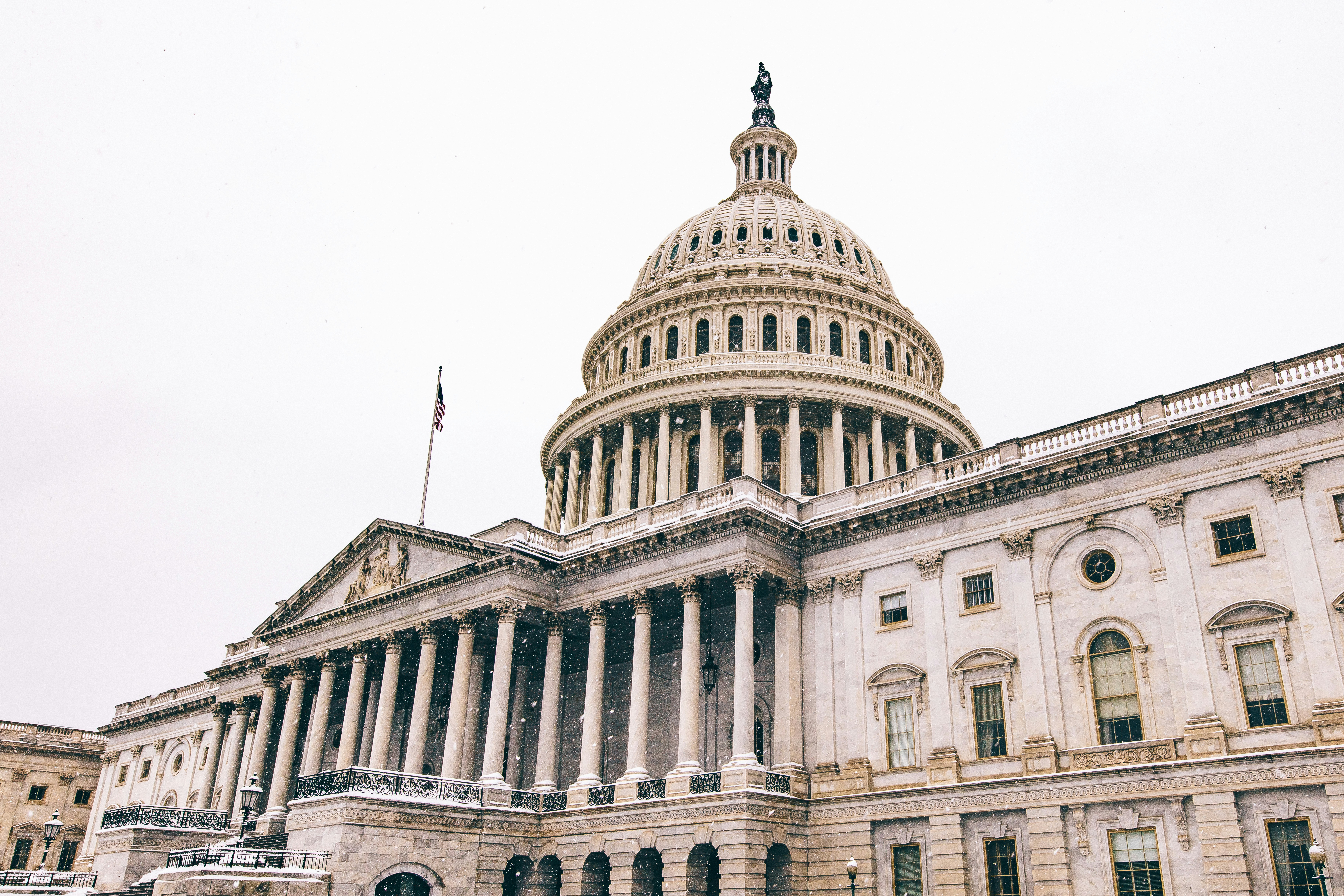 Spring snowfall covers the United States Capitol building | architectural photo of a beige mansion