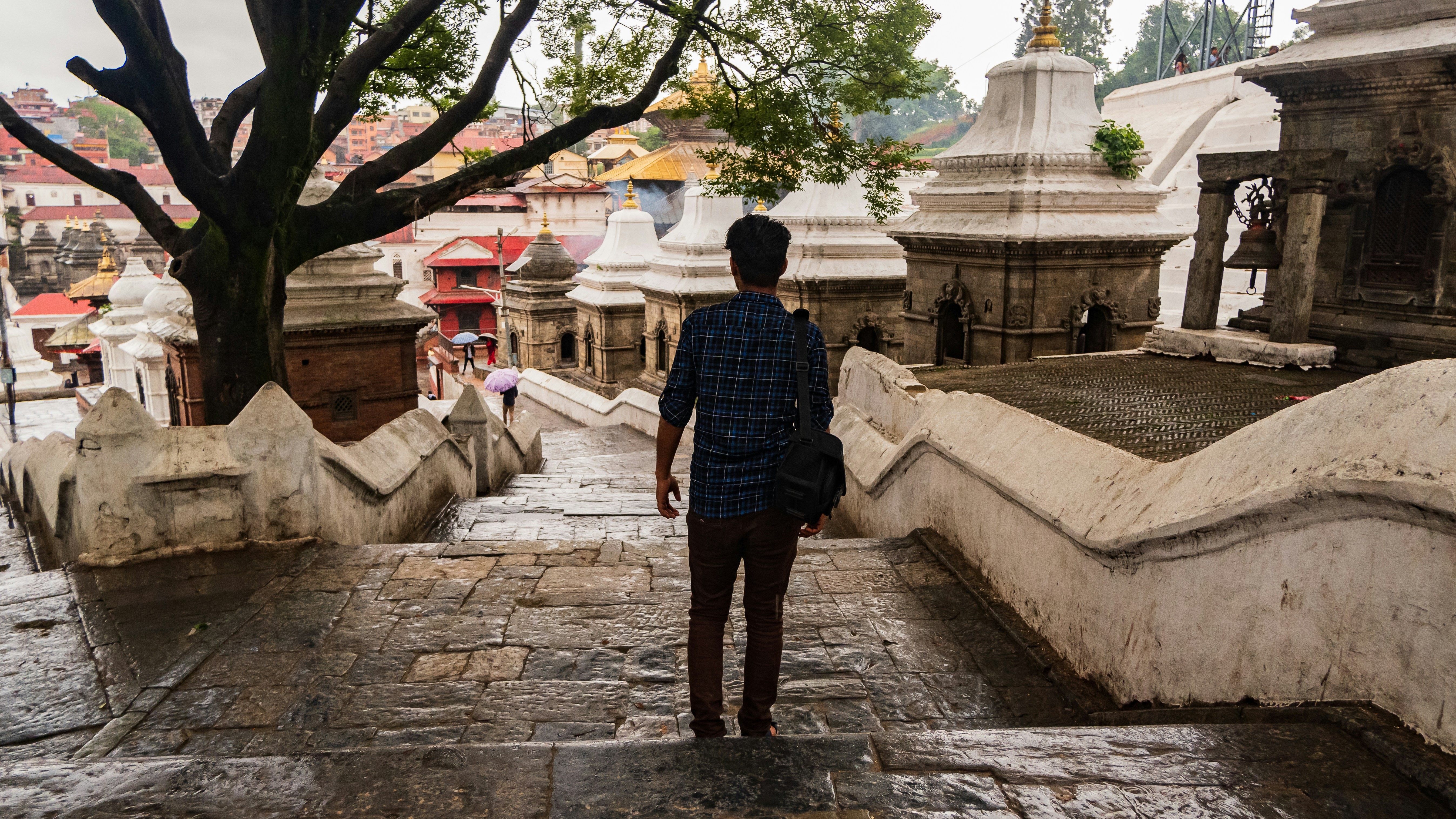 Person walking down ancient stone steps surrounded by historic architecture and lush greenery.