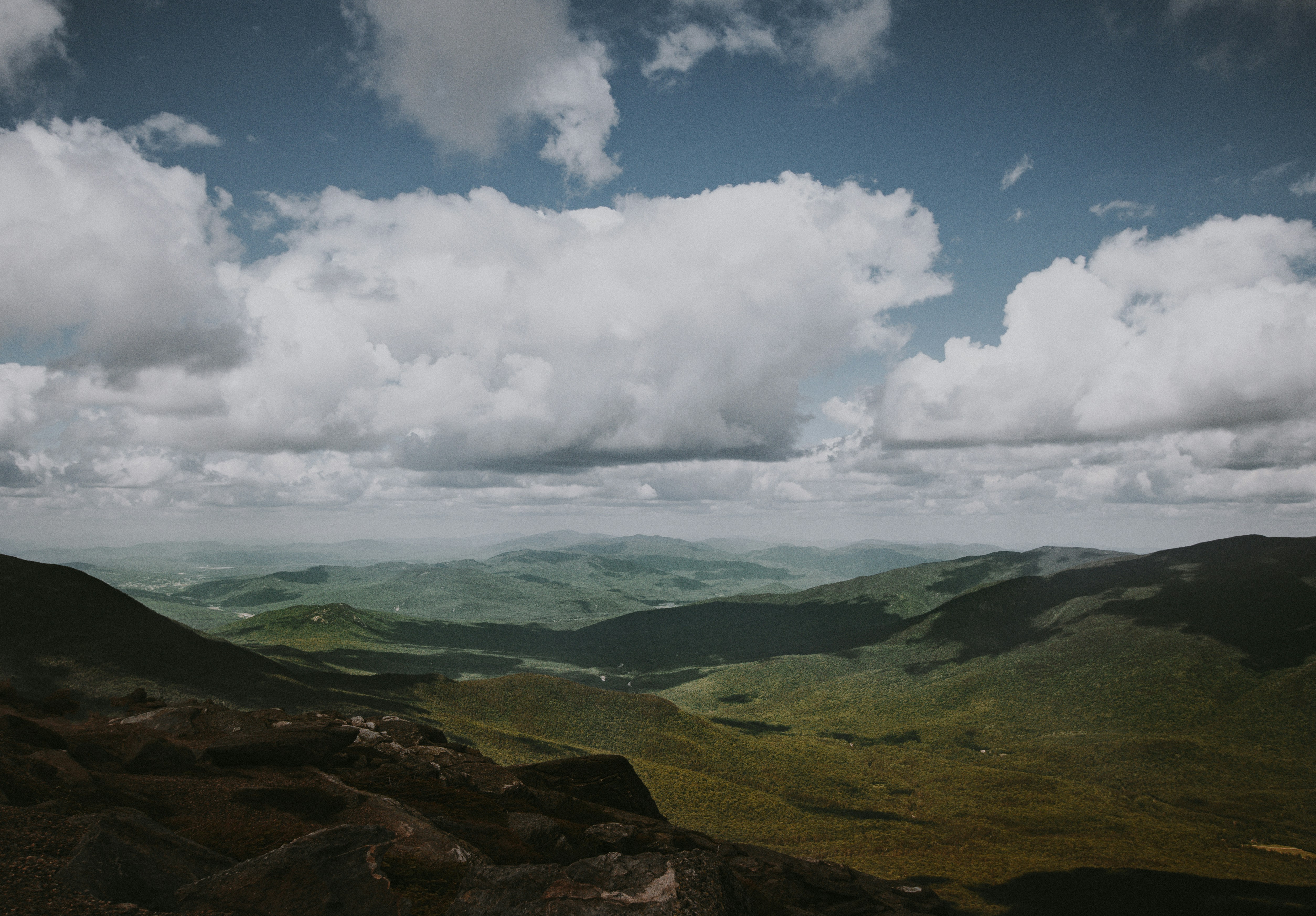 Vast landscape view from a mountain top under a sky filled with dramatic clouds.