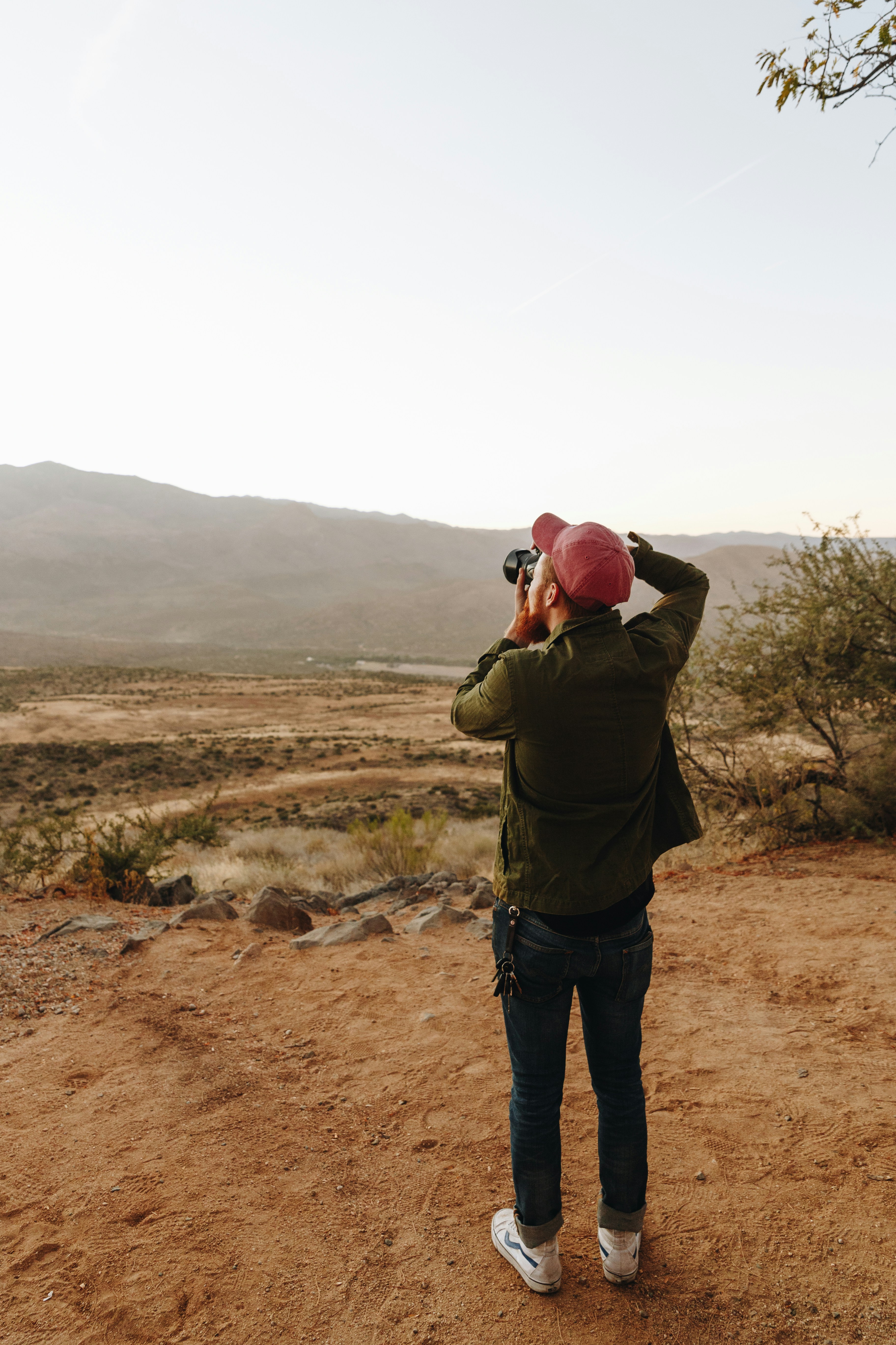 Desert Horizon Seeker: A Hatted Photographer Frames the Distant Range at Golden Hour