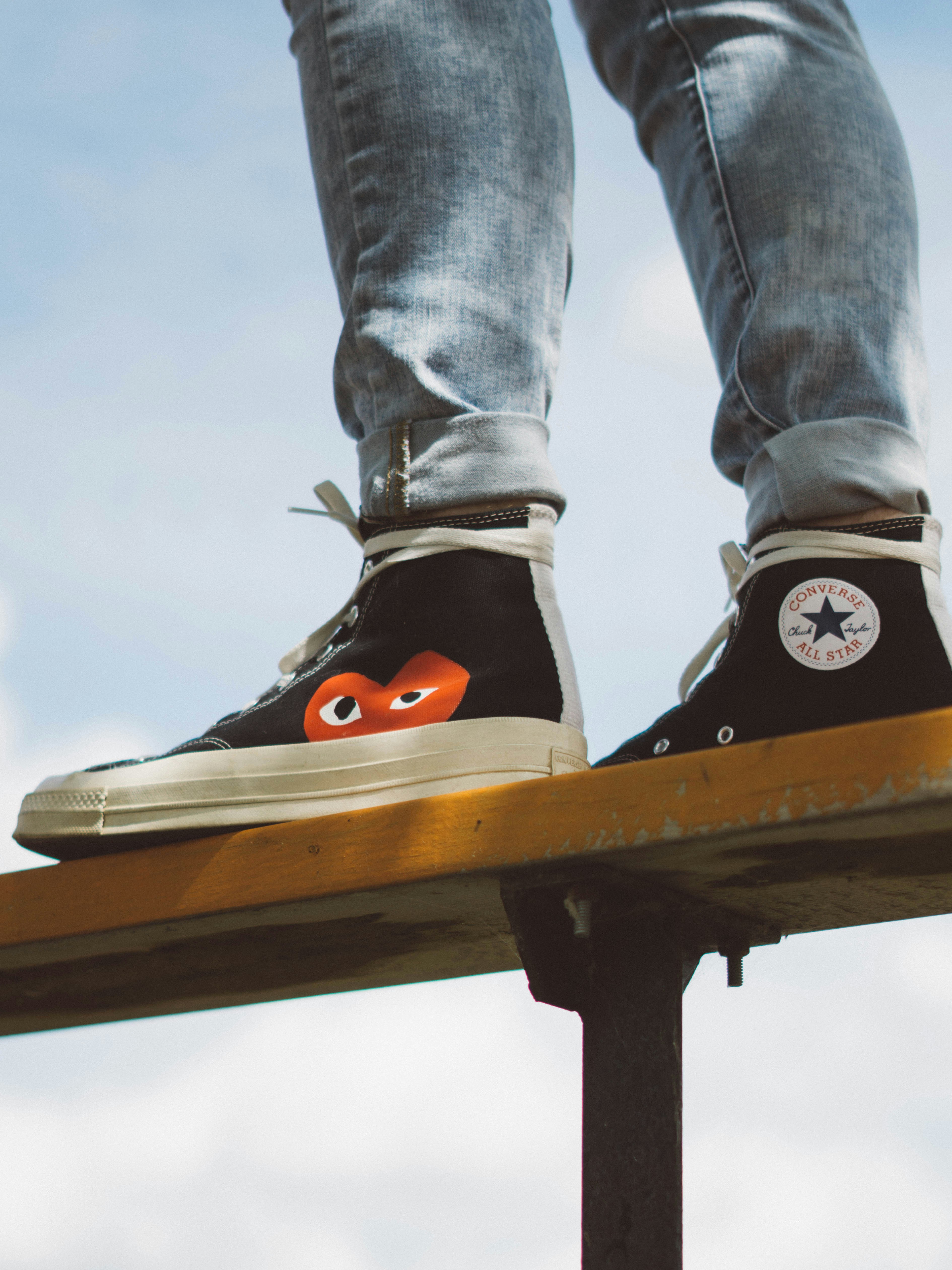 Balancing on a Narrow Beam: Play Logo Sneakers Against a Sky