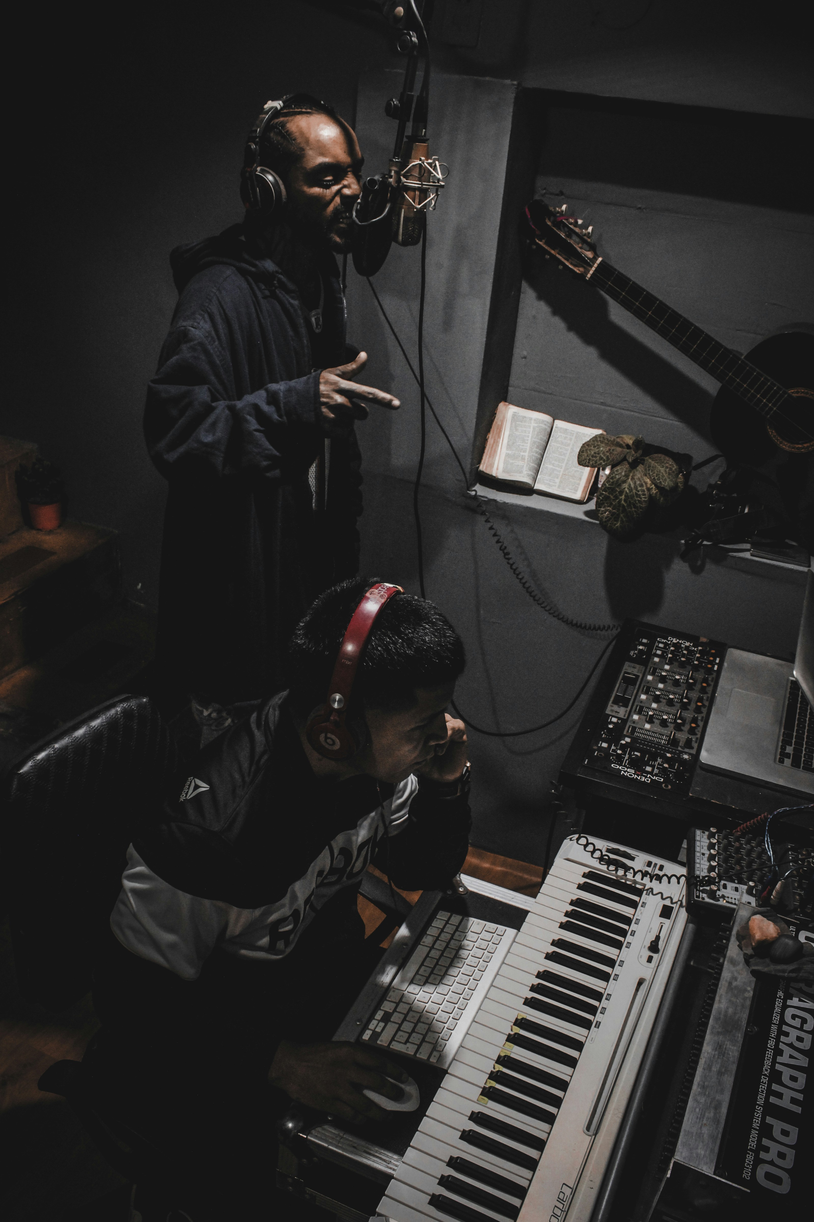 Man sitting in front on electronic keyboard beside man standing in ...