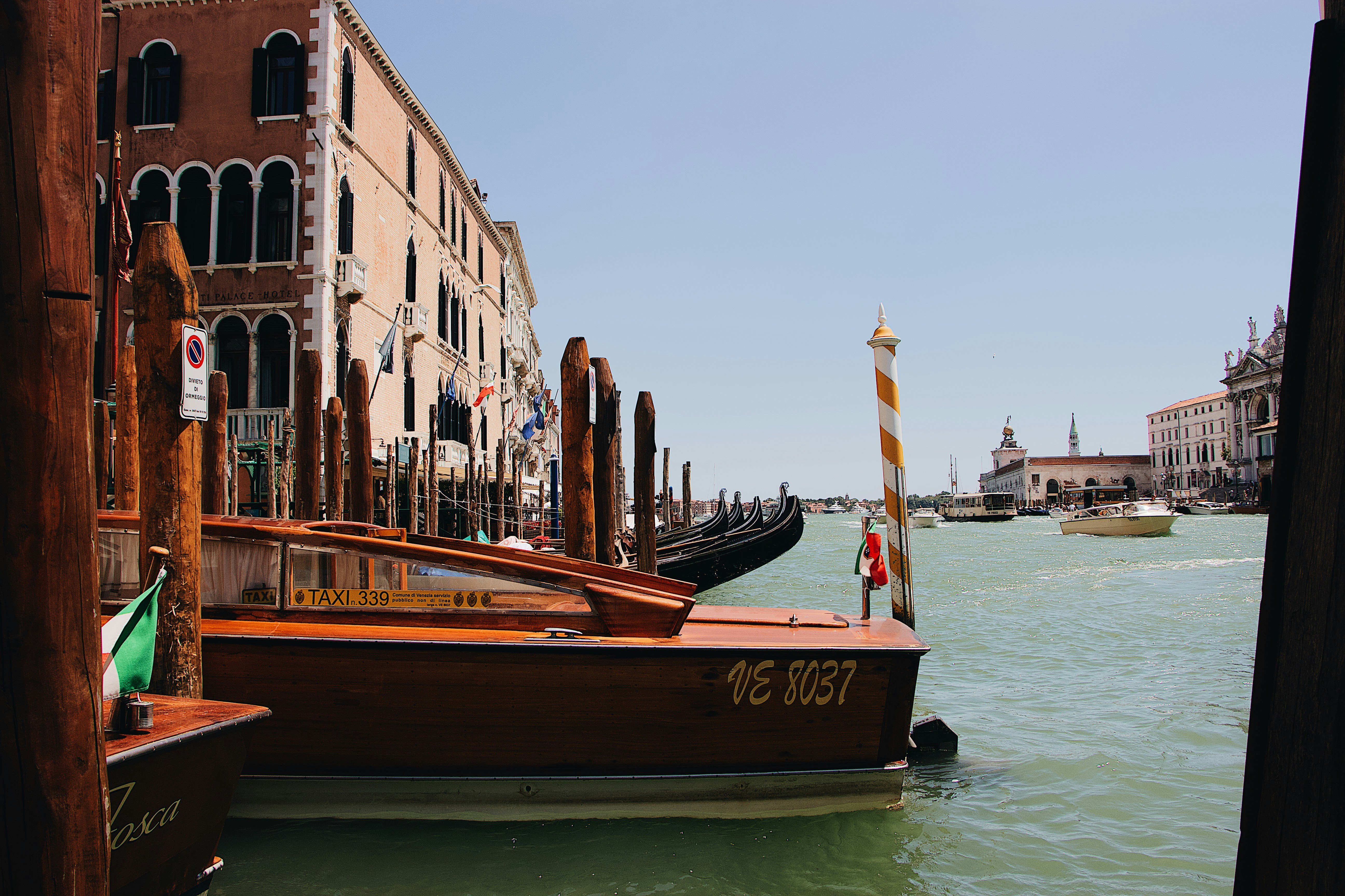 Moored in Venice: A Weathered Boat and a Striped Beacon on a Sunlit Canal