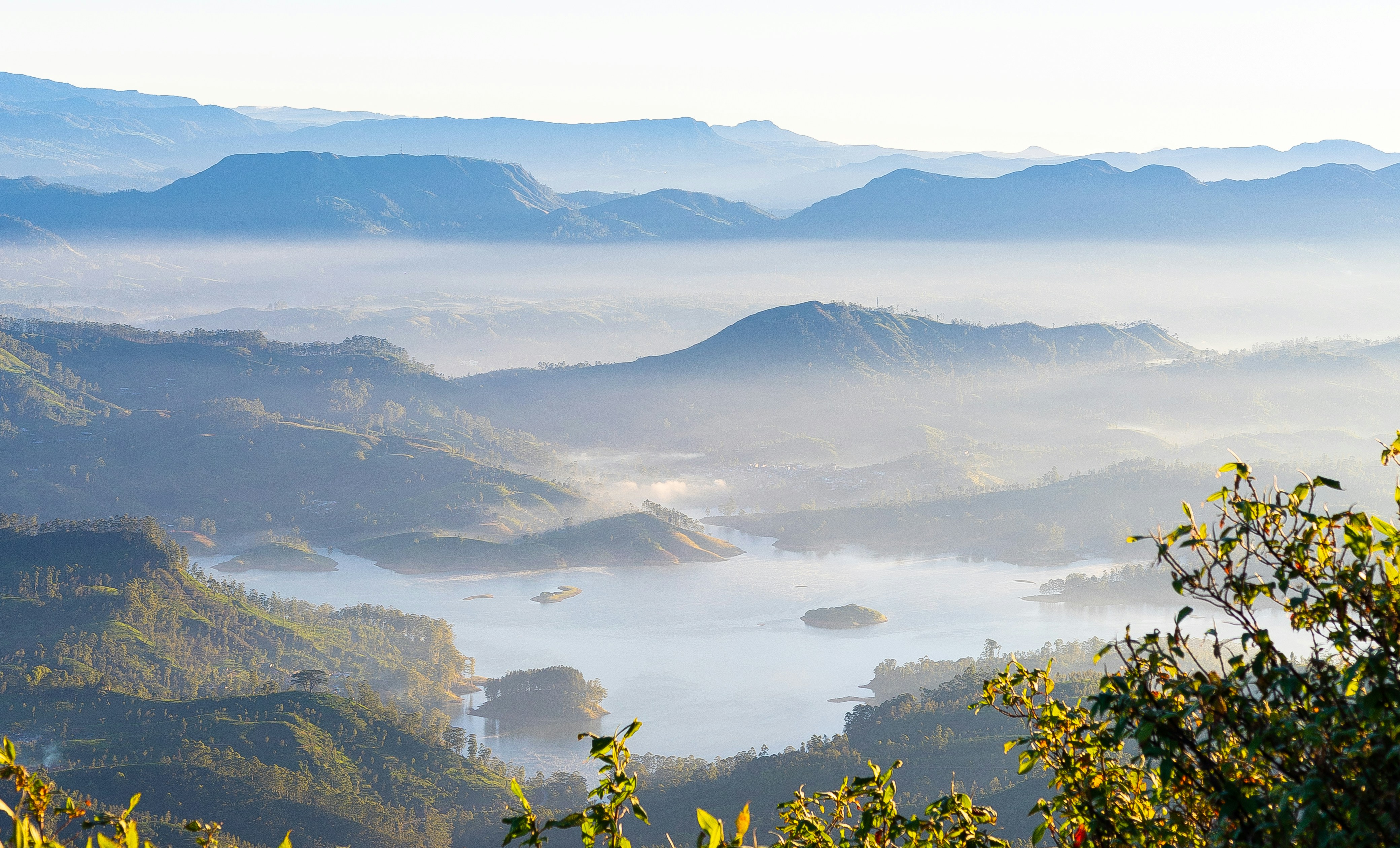 A serene landscape featuring rolling hills and a tranquil lake shrouded in morning mist, capturing the essence of a peaceful highland retreat.