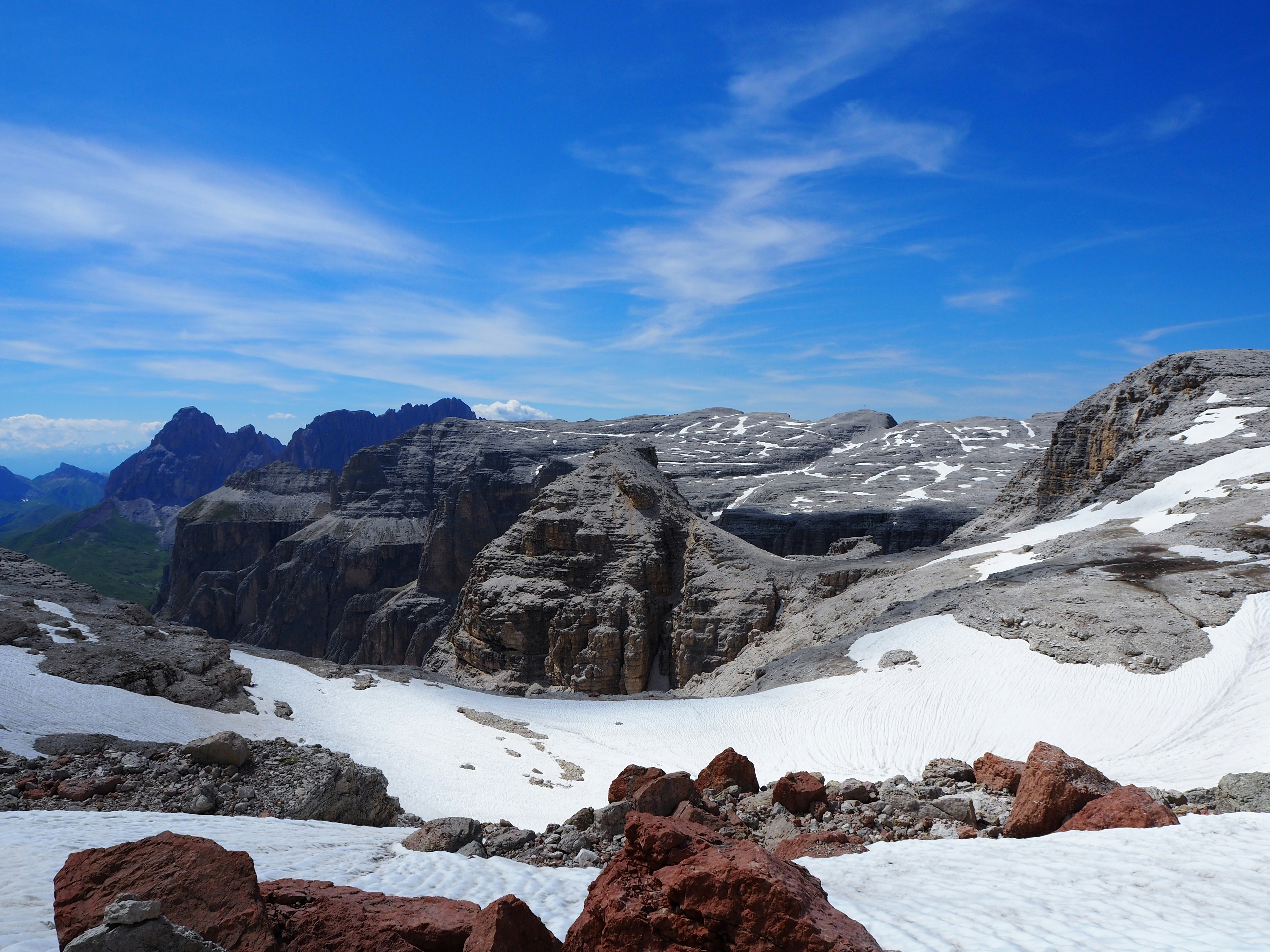 Snow-covered mountains under a bright blue sky with scattered clouds.
