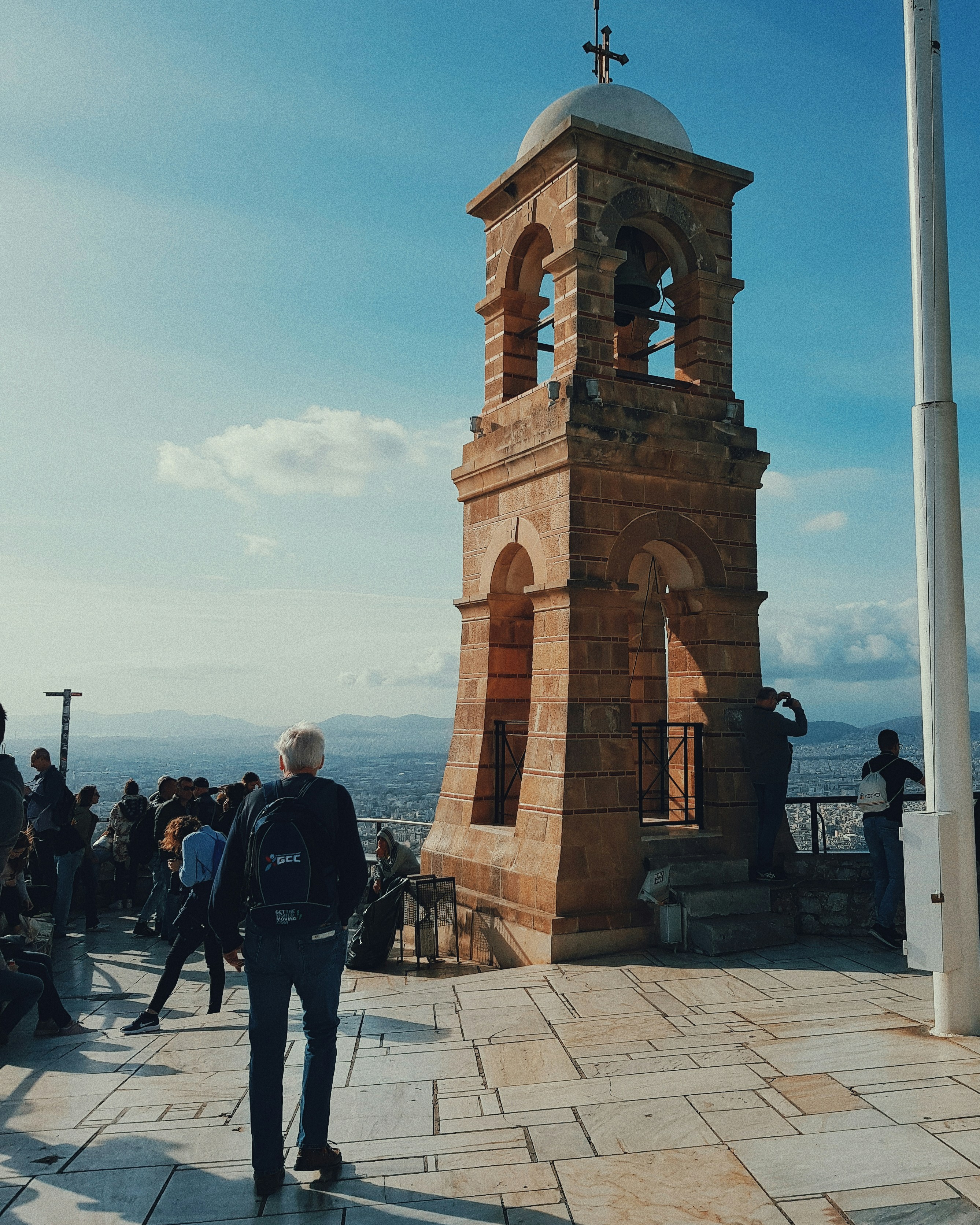 Stone Bell Tower Overlooking a Crowded Cliffside Plaza
