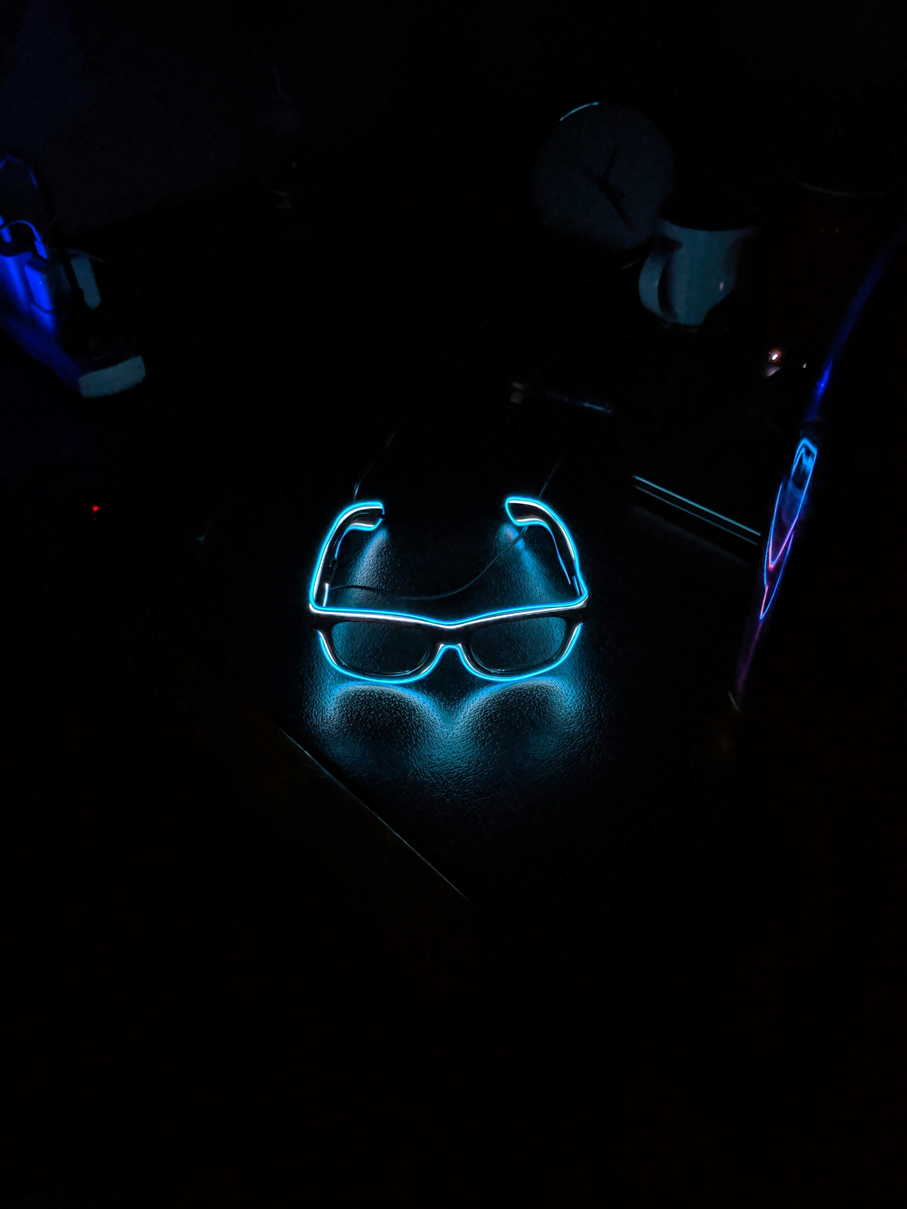 Cyan Neon Eyewear: Glowing Glasses on a Dim Desk