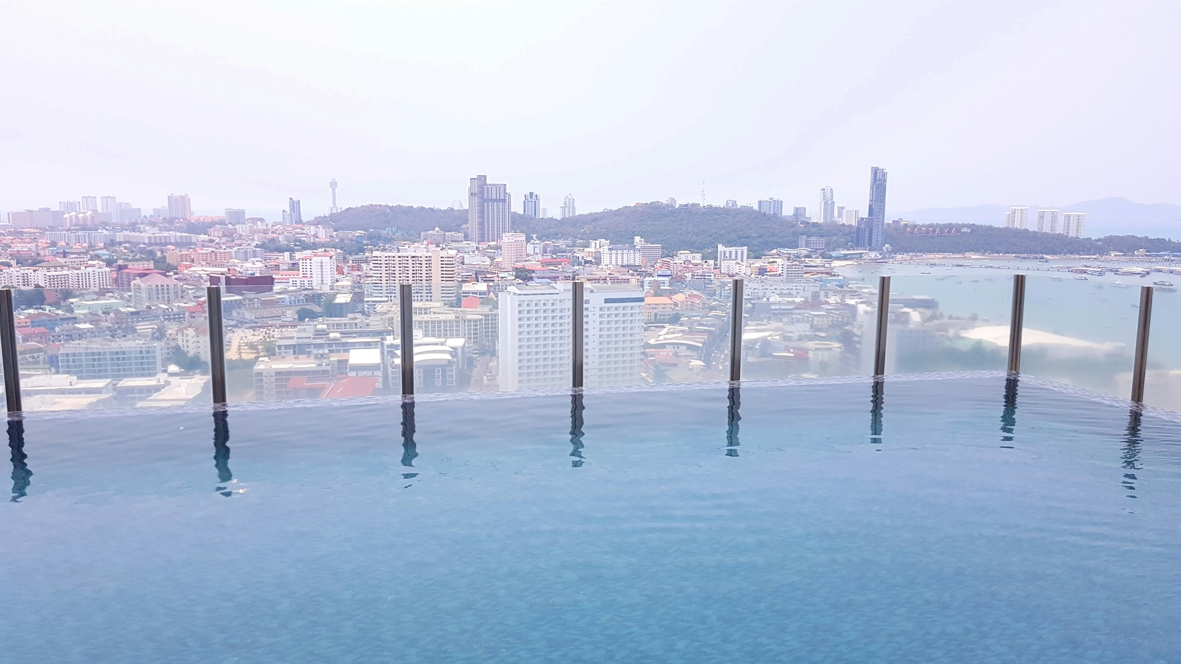 Horizon Over Glass: Infinity Pool Framing a Misty Coastal City