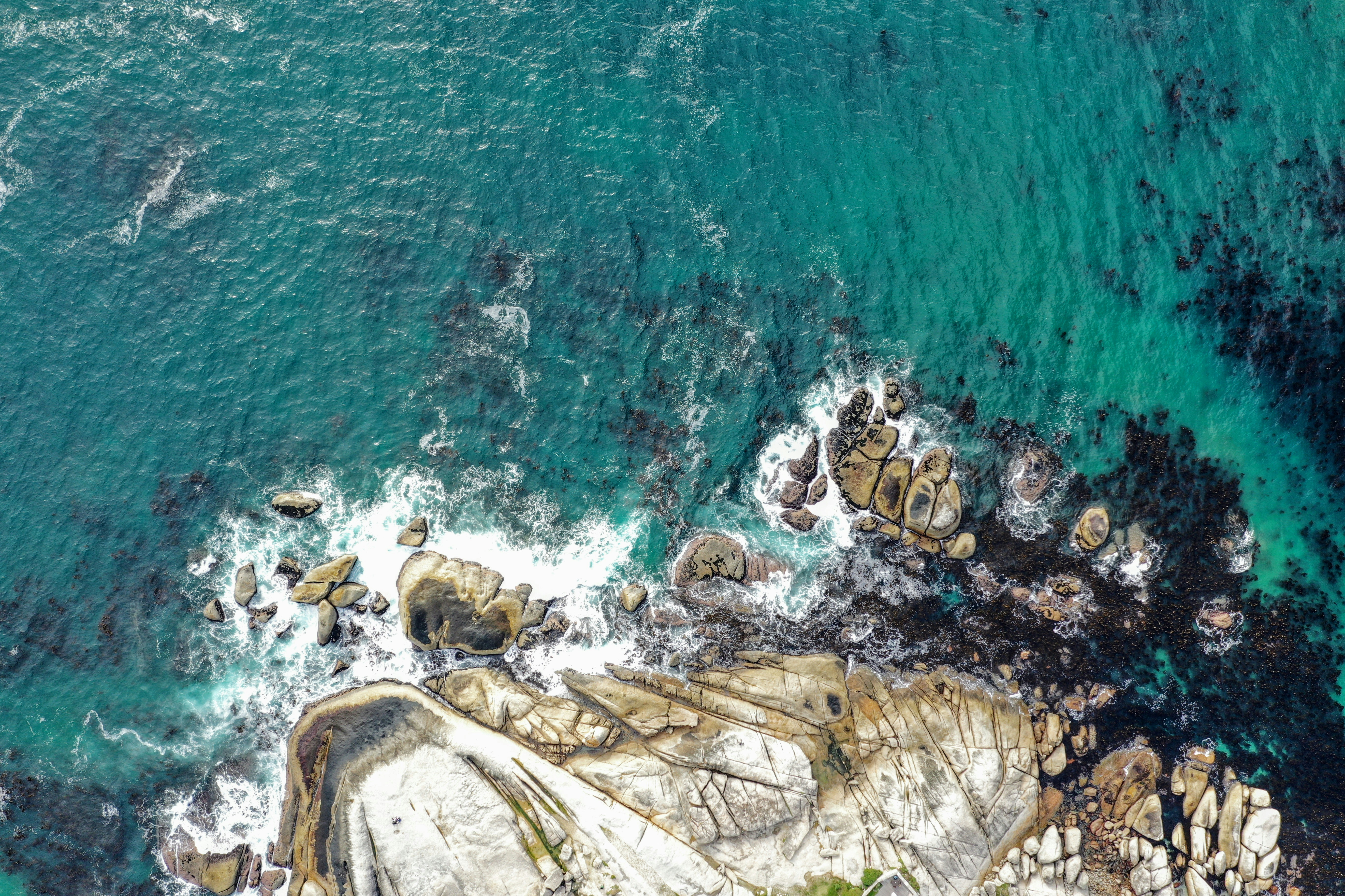Rocky coastline meets turquoise ocean waves from a high vantage point.