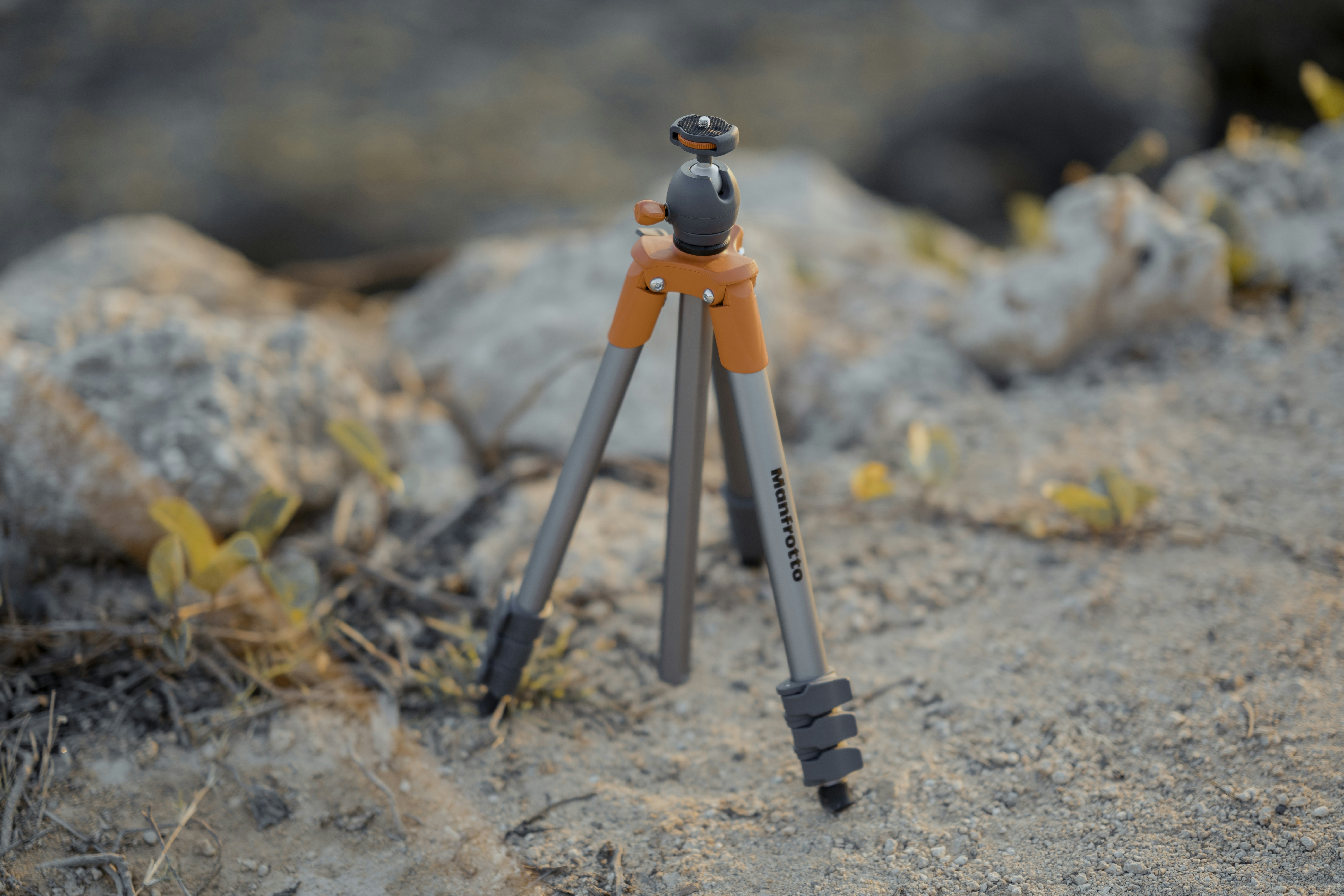 Orange-Accent Tripod Anchored on a Dusty Riverbank