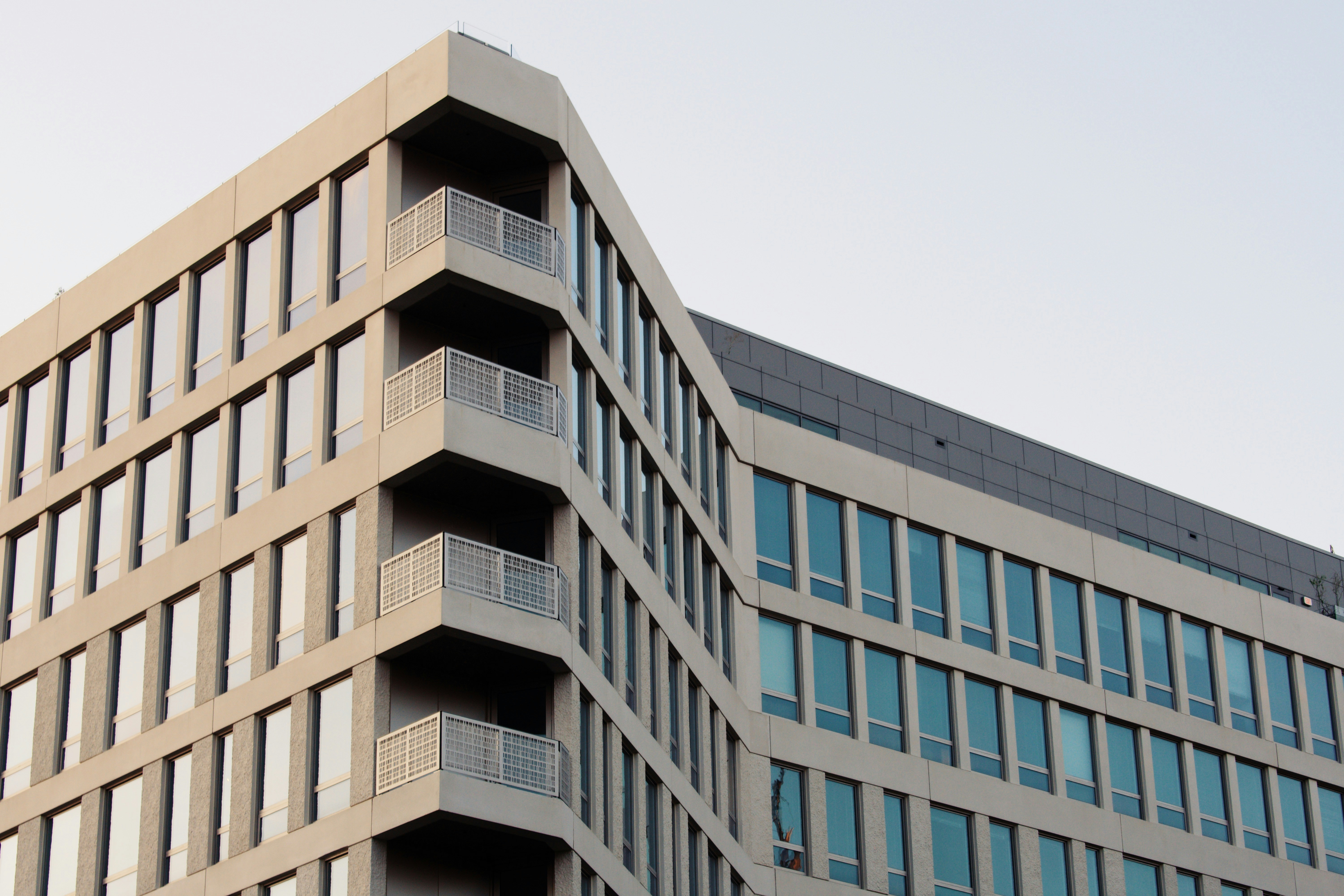 Modern building facade with angular lines and repetitive windows under clear sky.