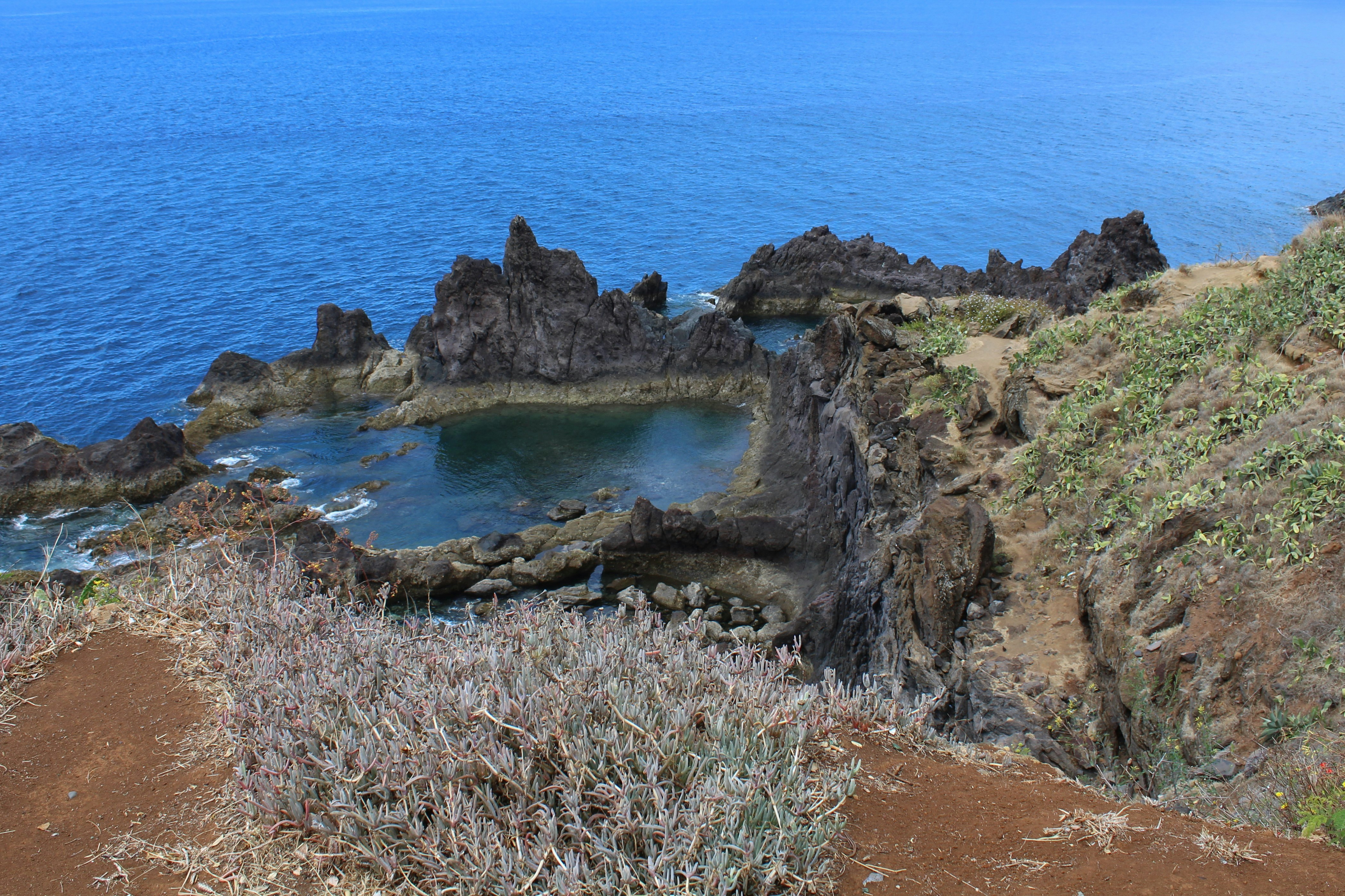 Blue tidal pool nestled among jagged basalt on a cliffside coast