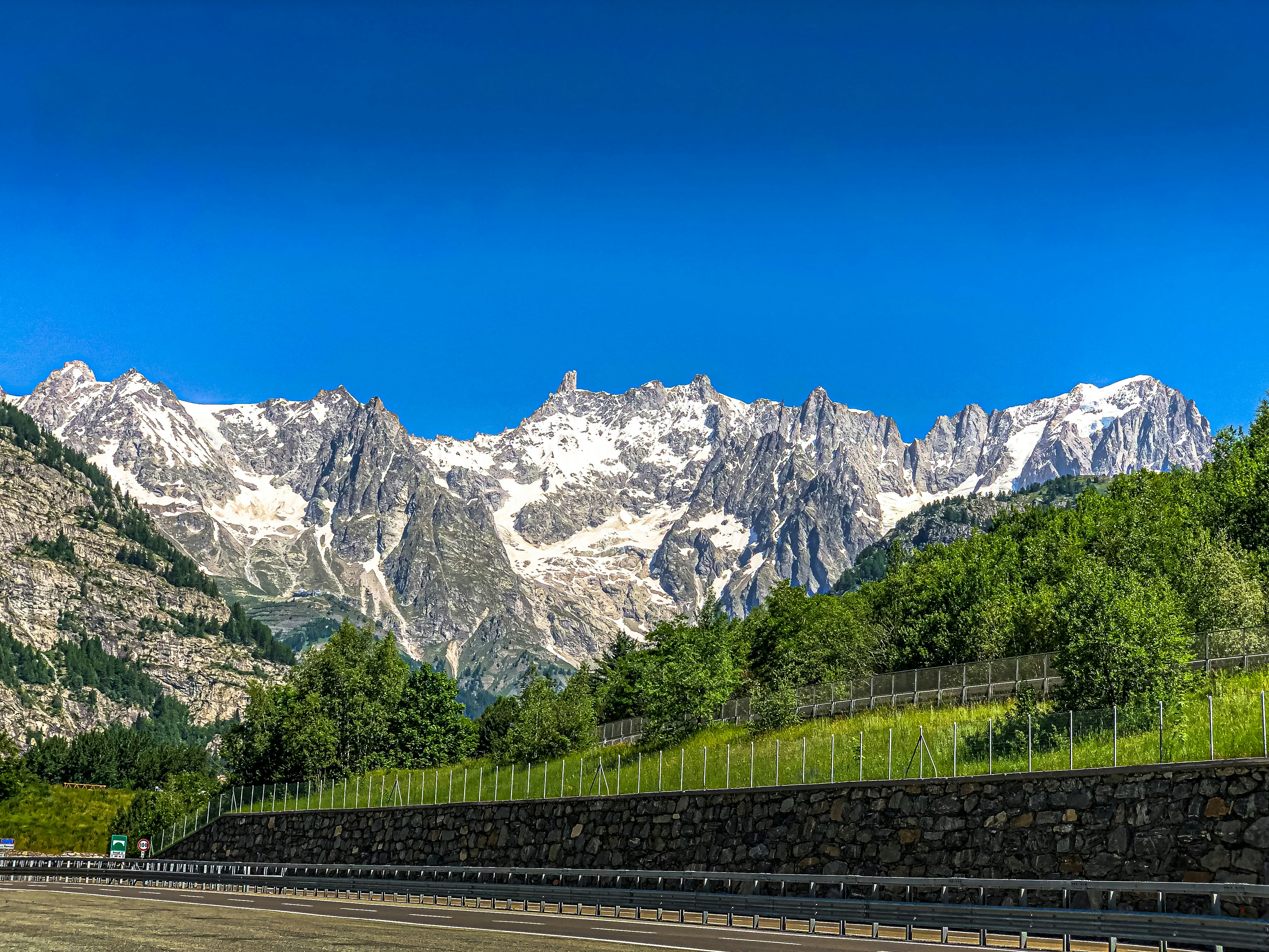 Snow-Kissed Alpine Peaks Over a Quiet Green Corridor