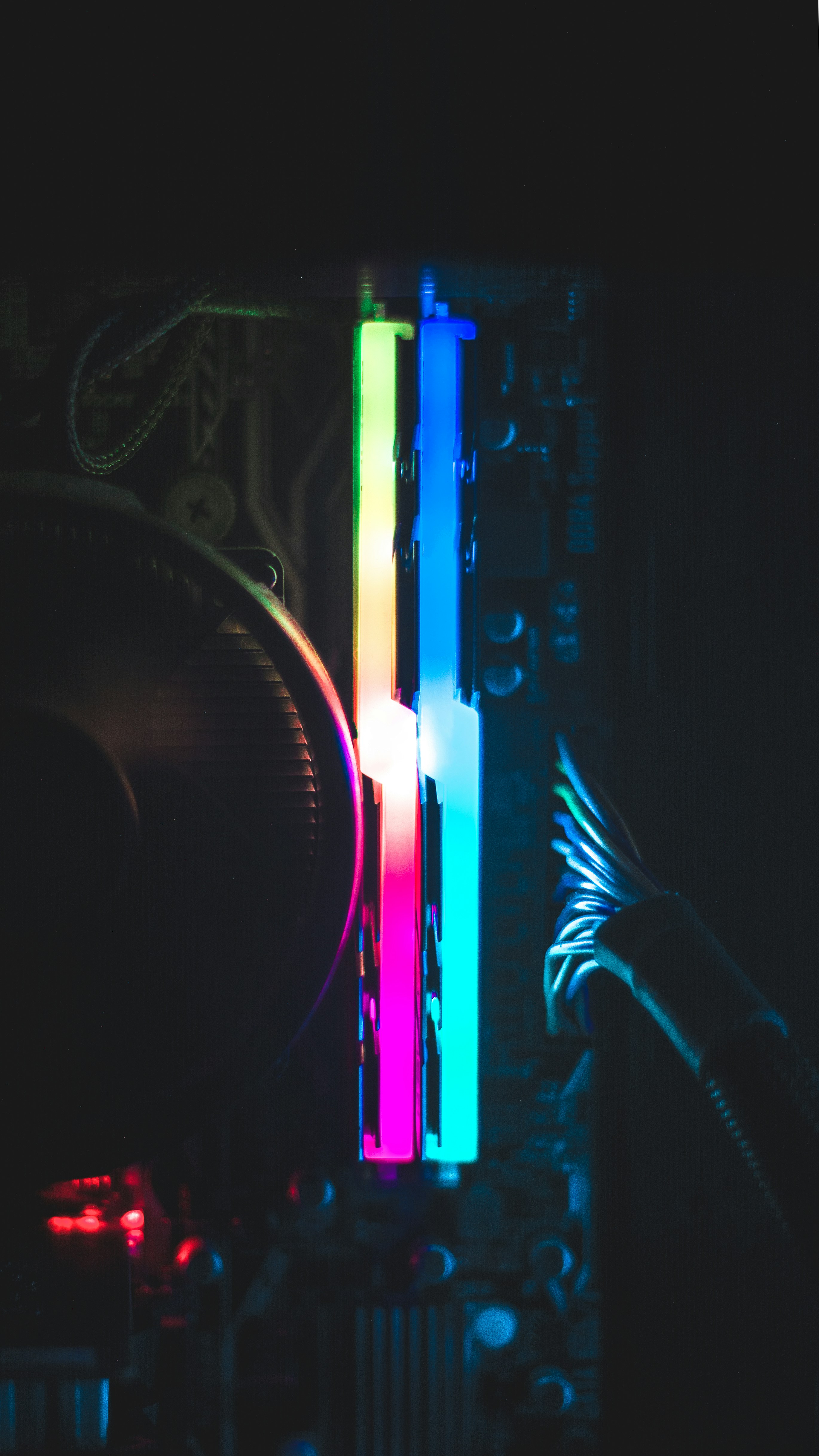Vibrant RGB RAM modules illuminate a dark computer motherboard, showcasing intricate circuitry. The contrast highlights the technological elegance of modern computing.