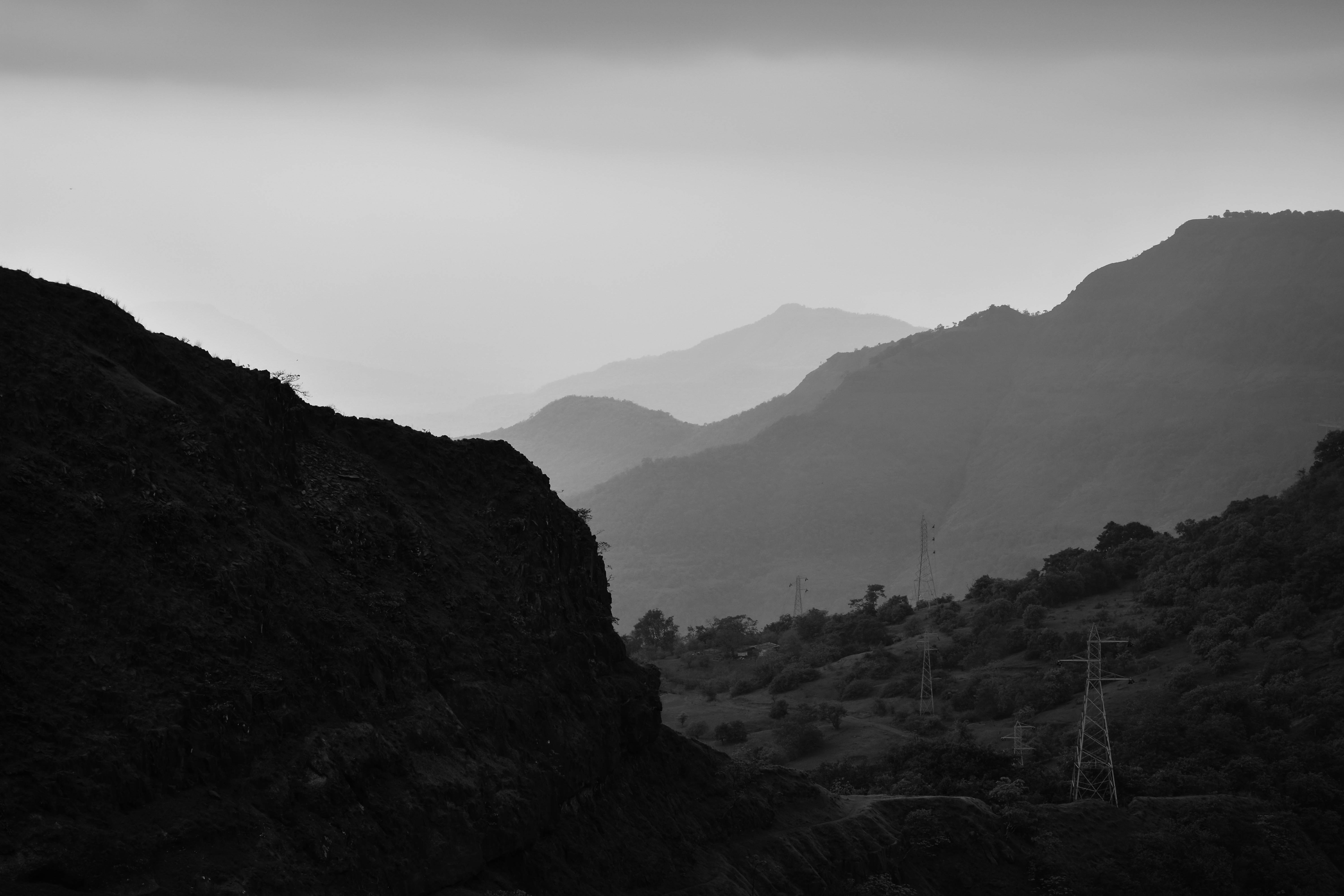 Layered mountain silhouettes fade into the distance under a cloudy sky, creating a serene and atmospheric landscape. The composition emphasizes depth and the tranquility of nature.