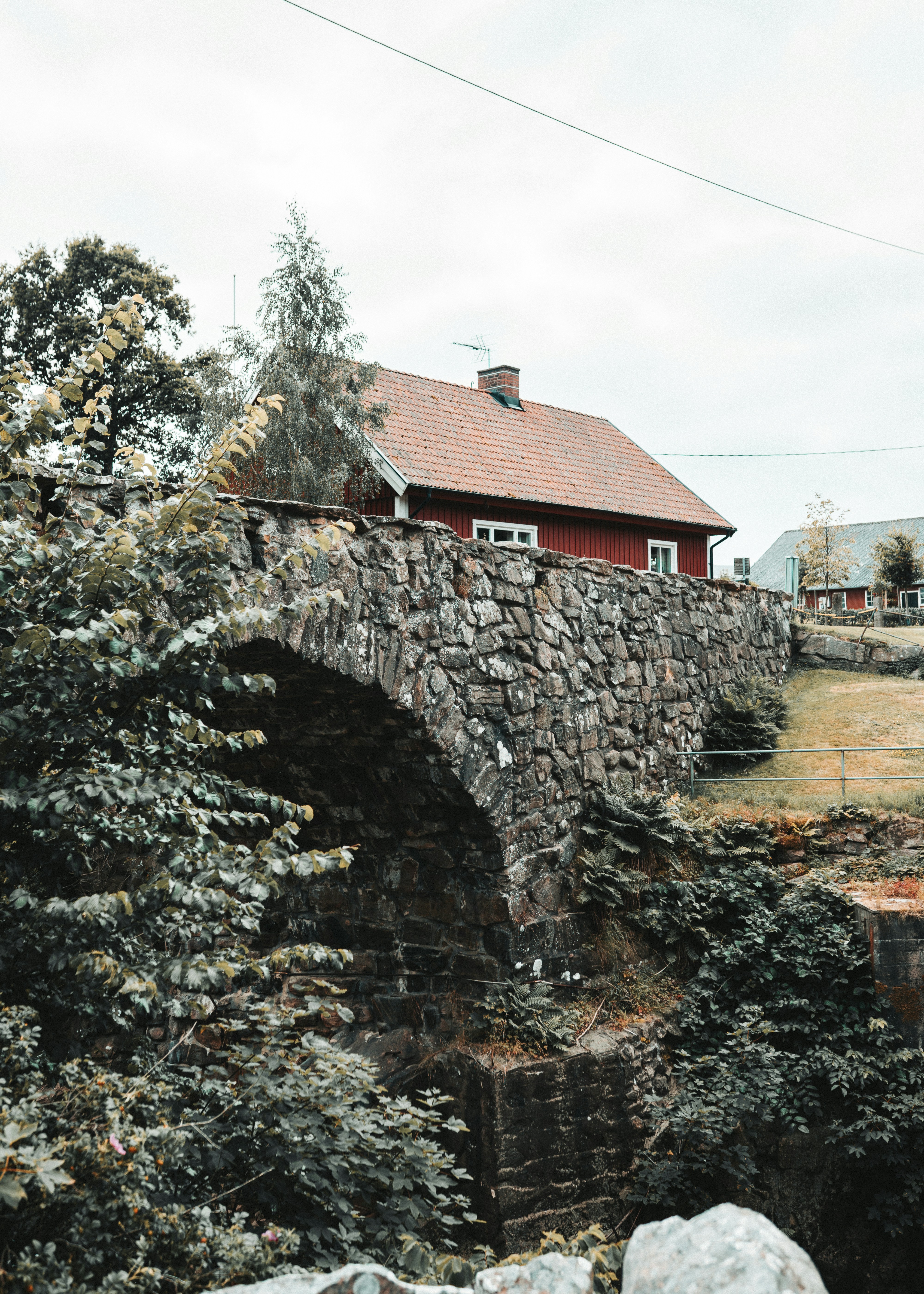 a stone bridge with a red building in the background