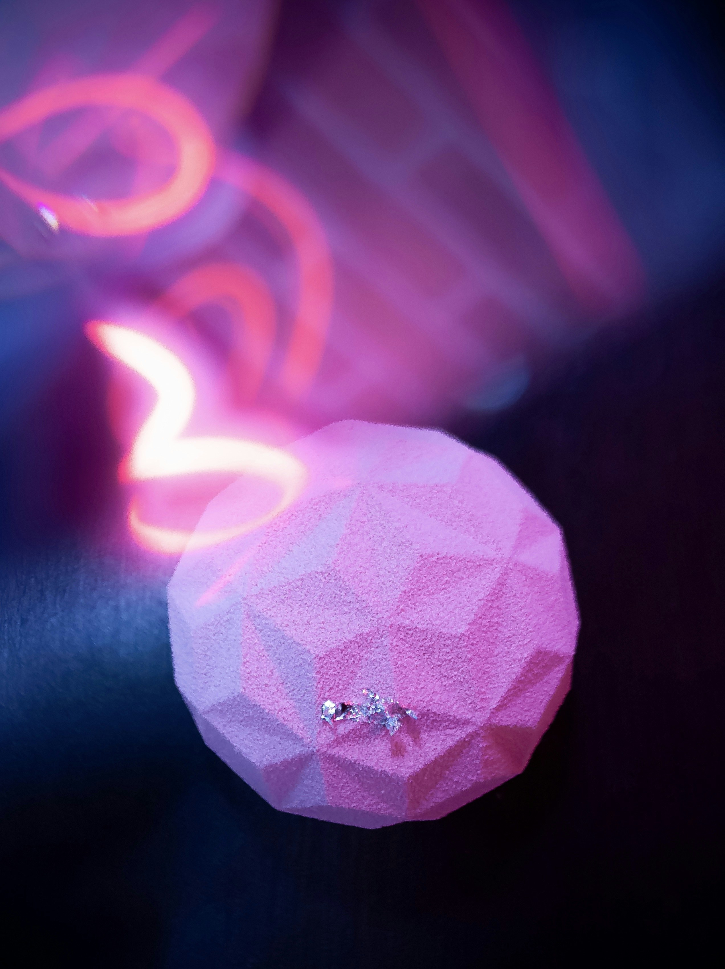 Faceted Pink Orb Under Neon Trails, with a Tiny Diamond Gleam