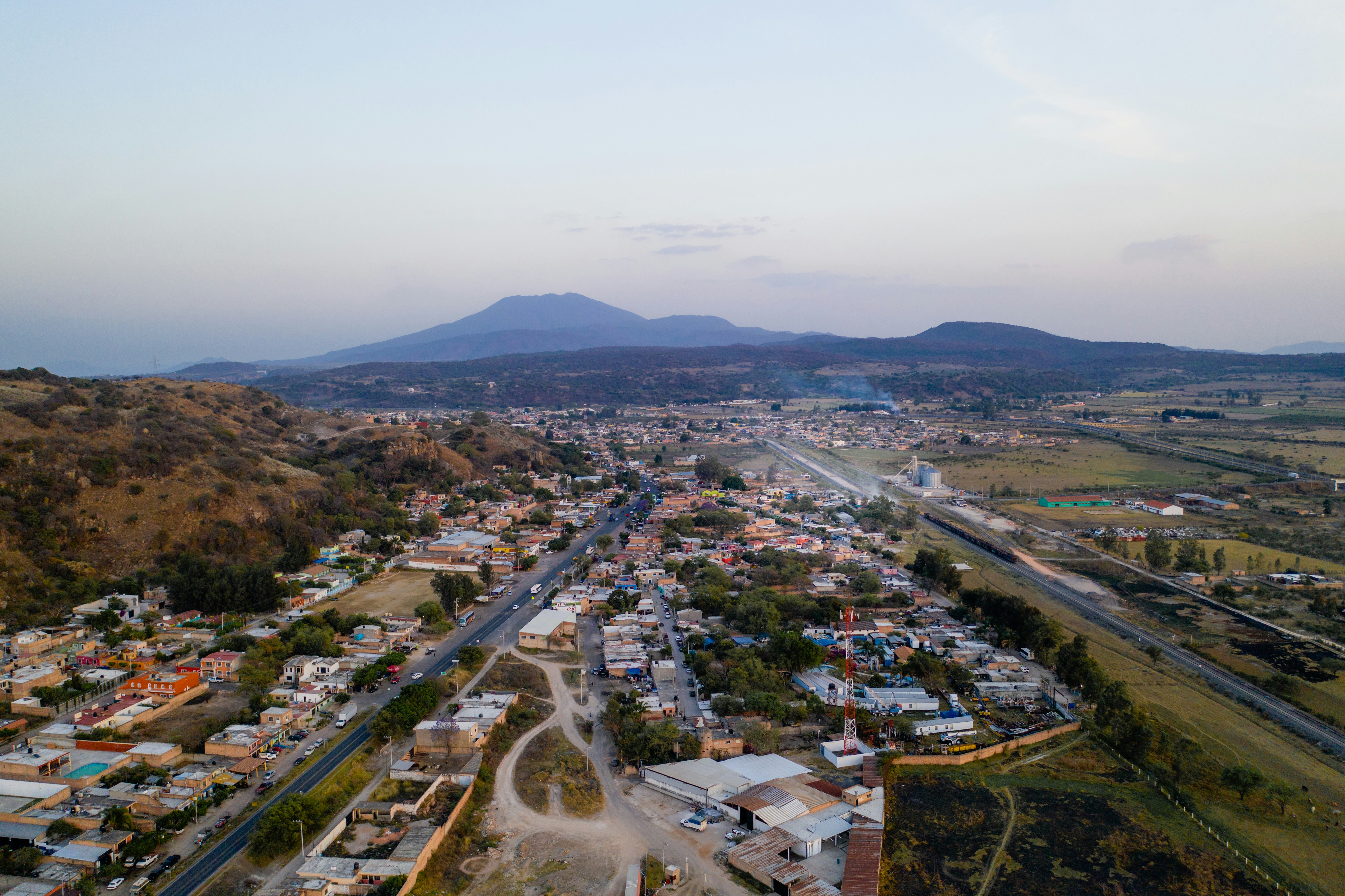 Aerial view of a small town nestled in a valley with distant mountains under a clear sky.