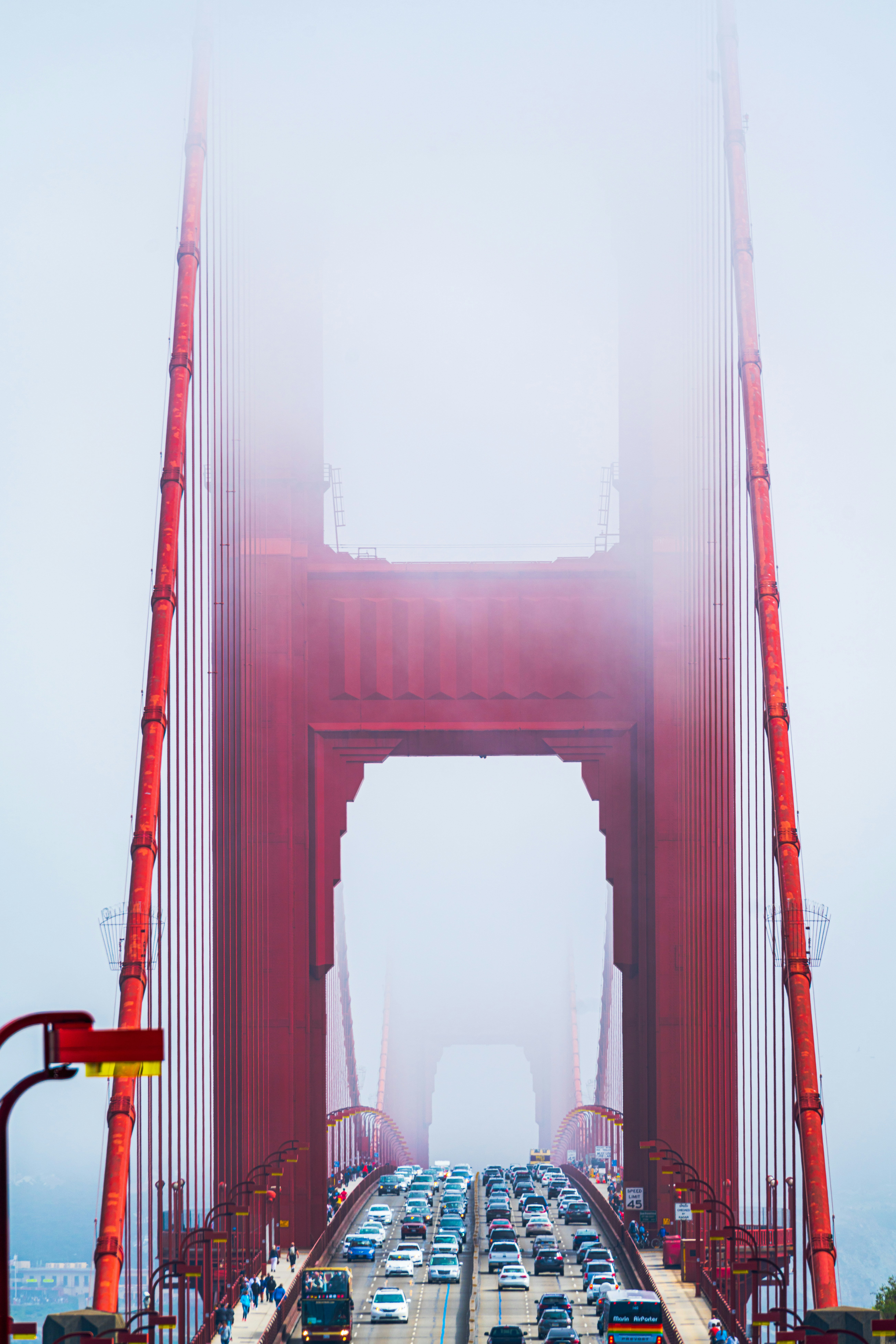 Golden Gate Bridge emerging from dense fog, showcasing its iconic towers and bustling traffic below.