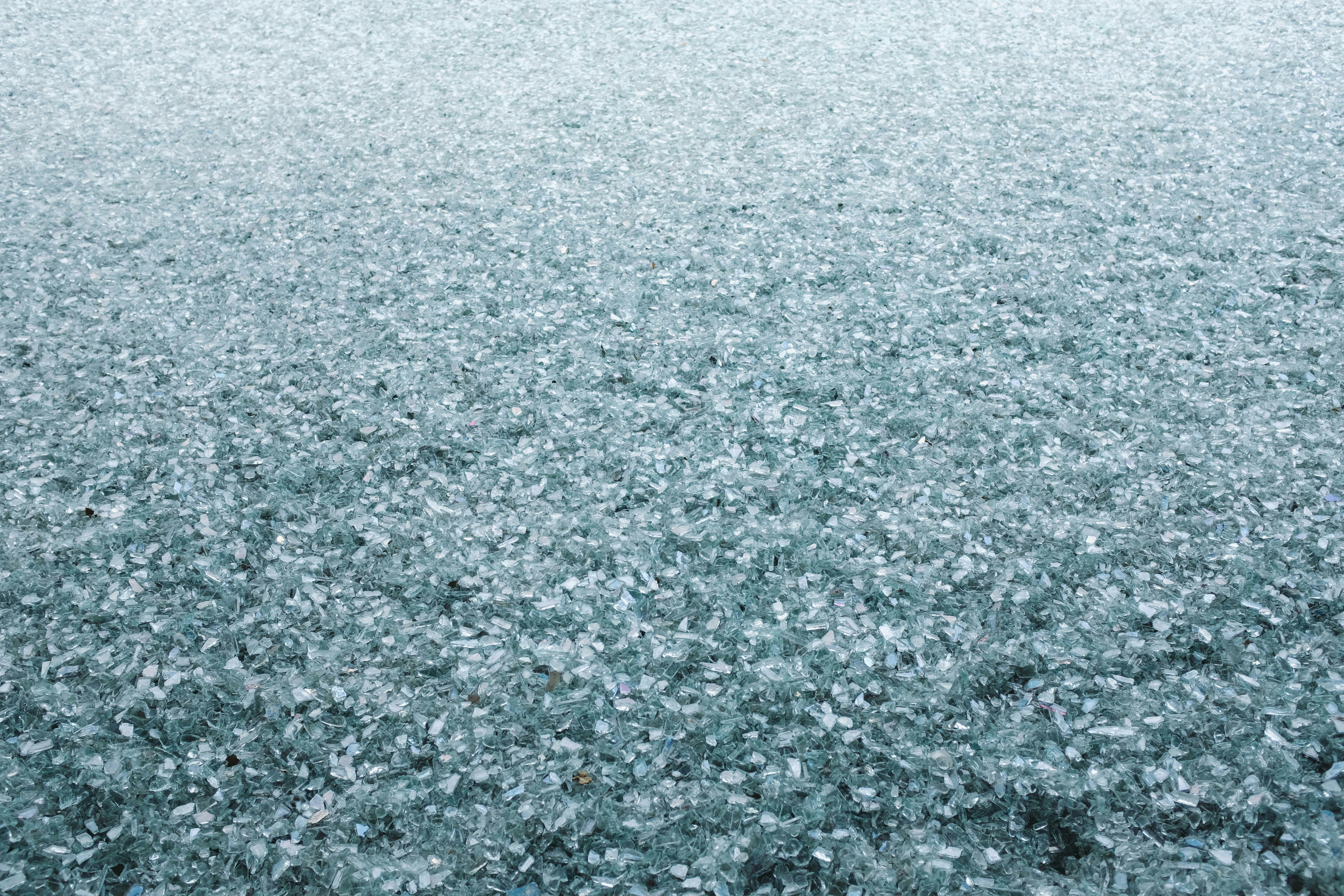 Expansive field of small, glistening glass shards creating a textured surface.