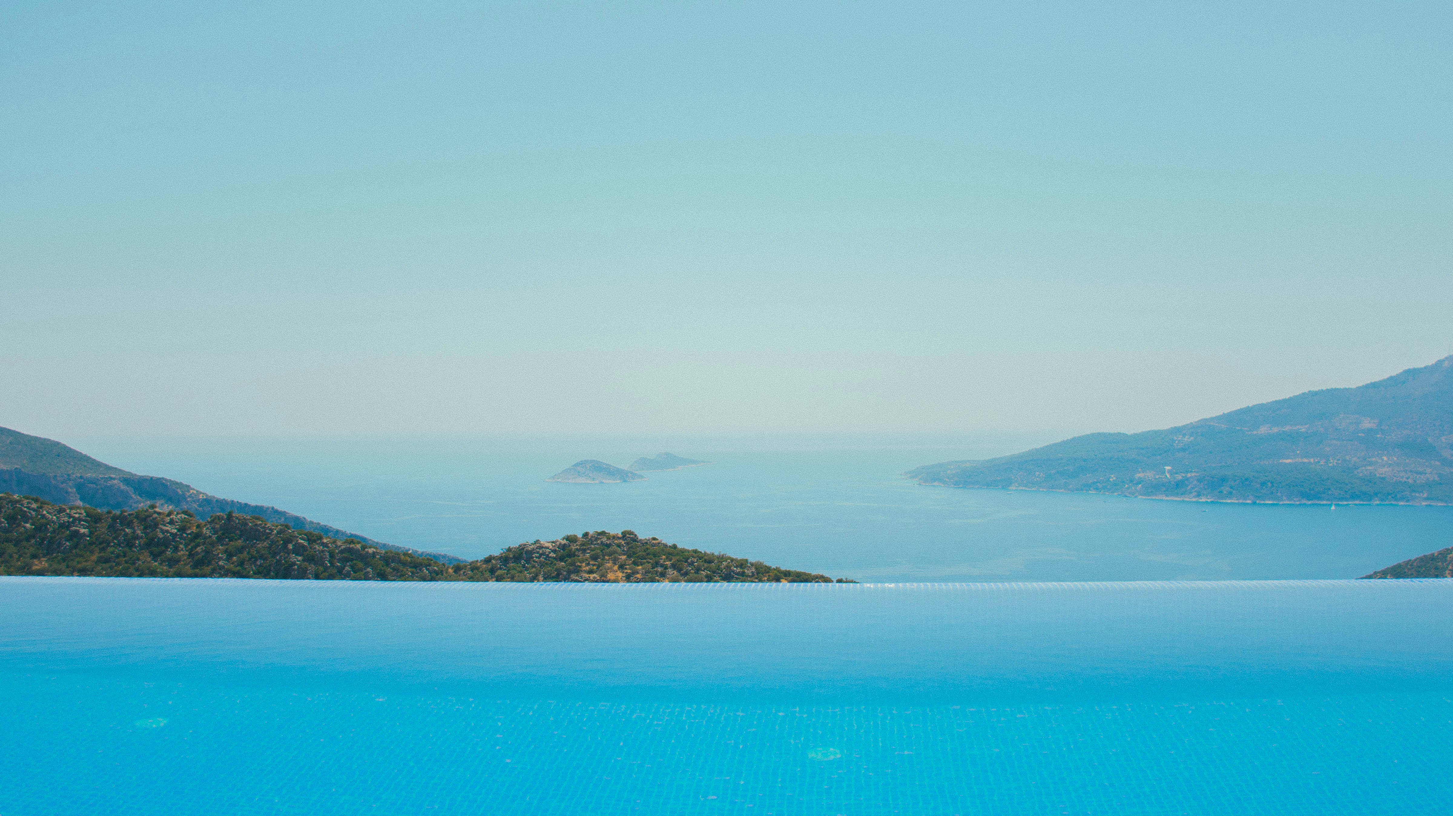 Infinity pool overlooking serene blue sea and distant islands under a clear sky.