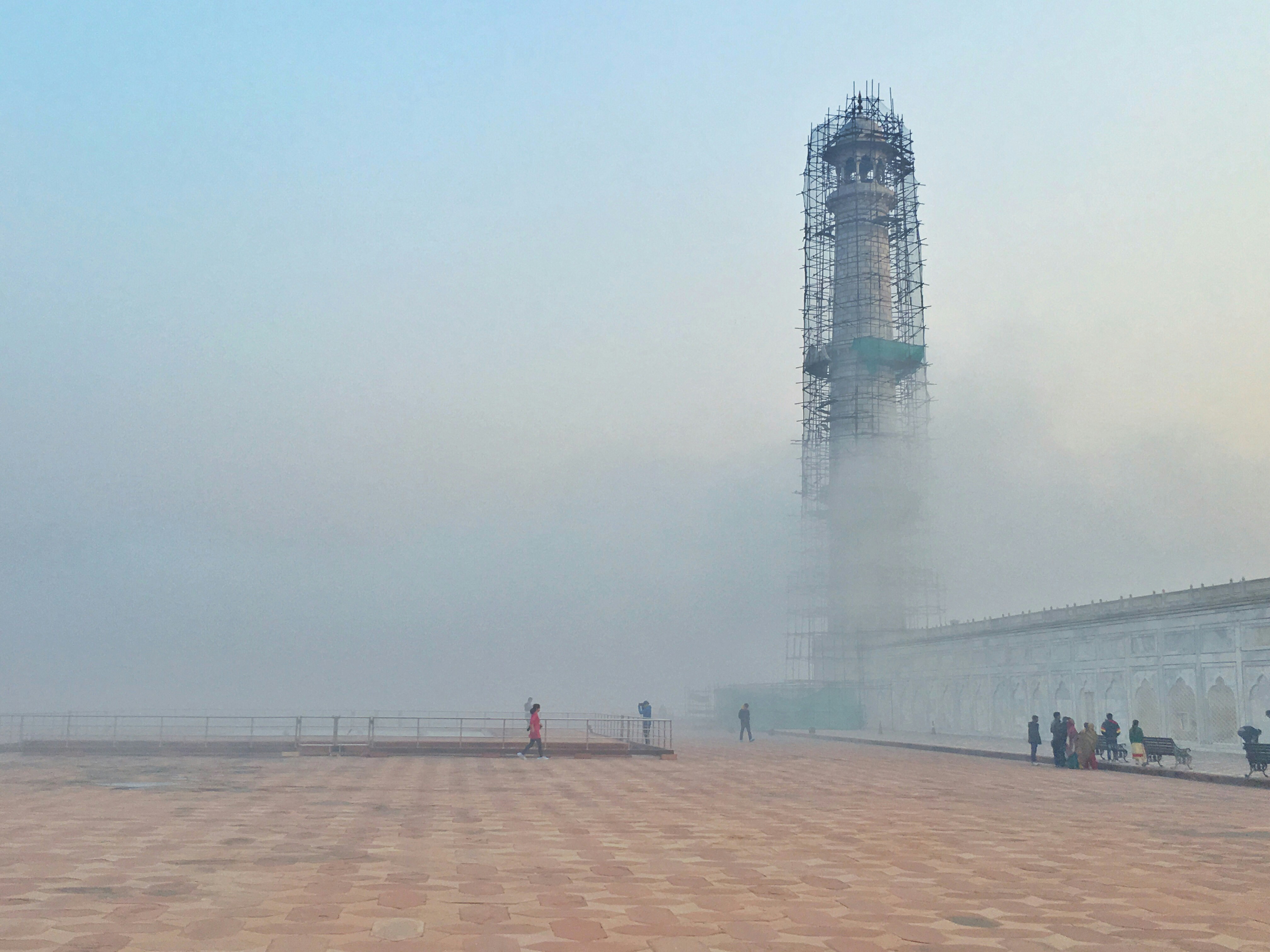 Tower in the Mist: Scaffold Sentinel Over a Quiet Promenade