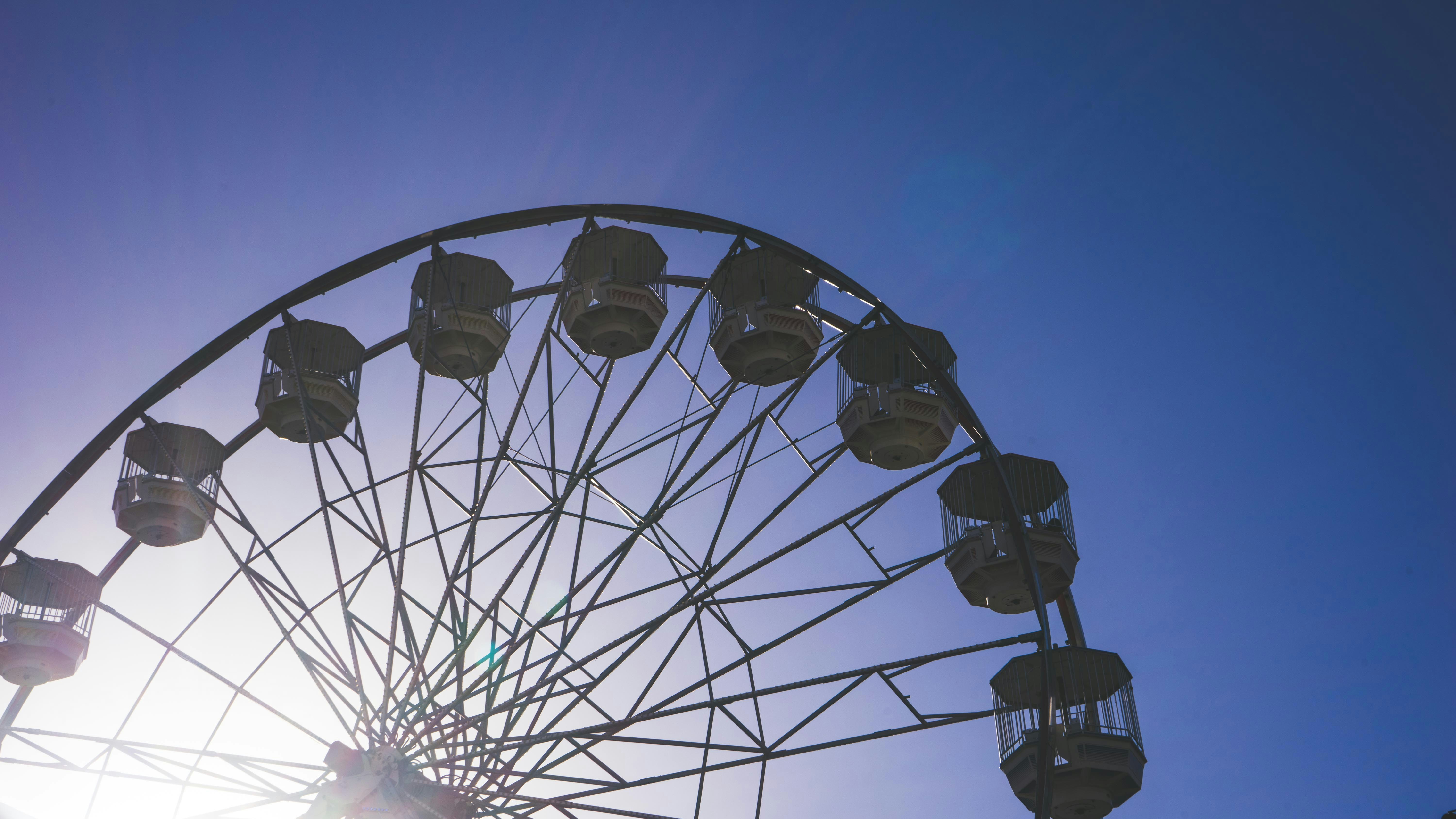 Ferris wheel silhouetted against a bright blue sky, highlighting its geometric structure and the playful spirit of amusement parks.