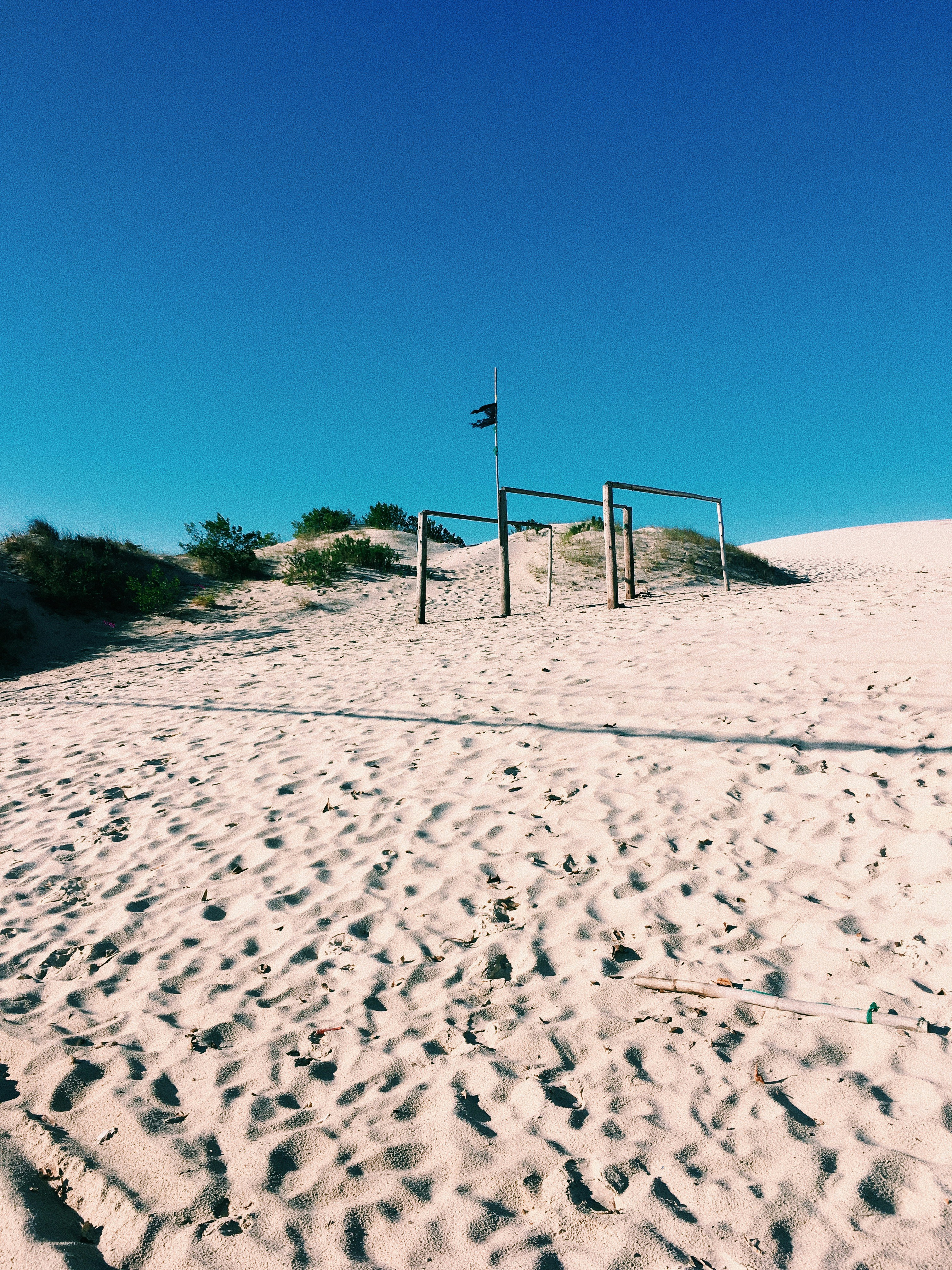 Deserted Sandfield with Weathered Goalposts Under a Cerulean Sky