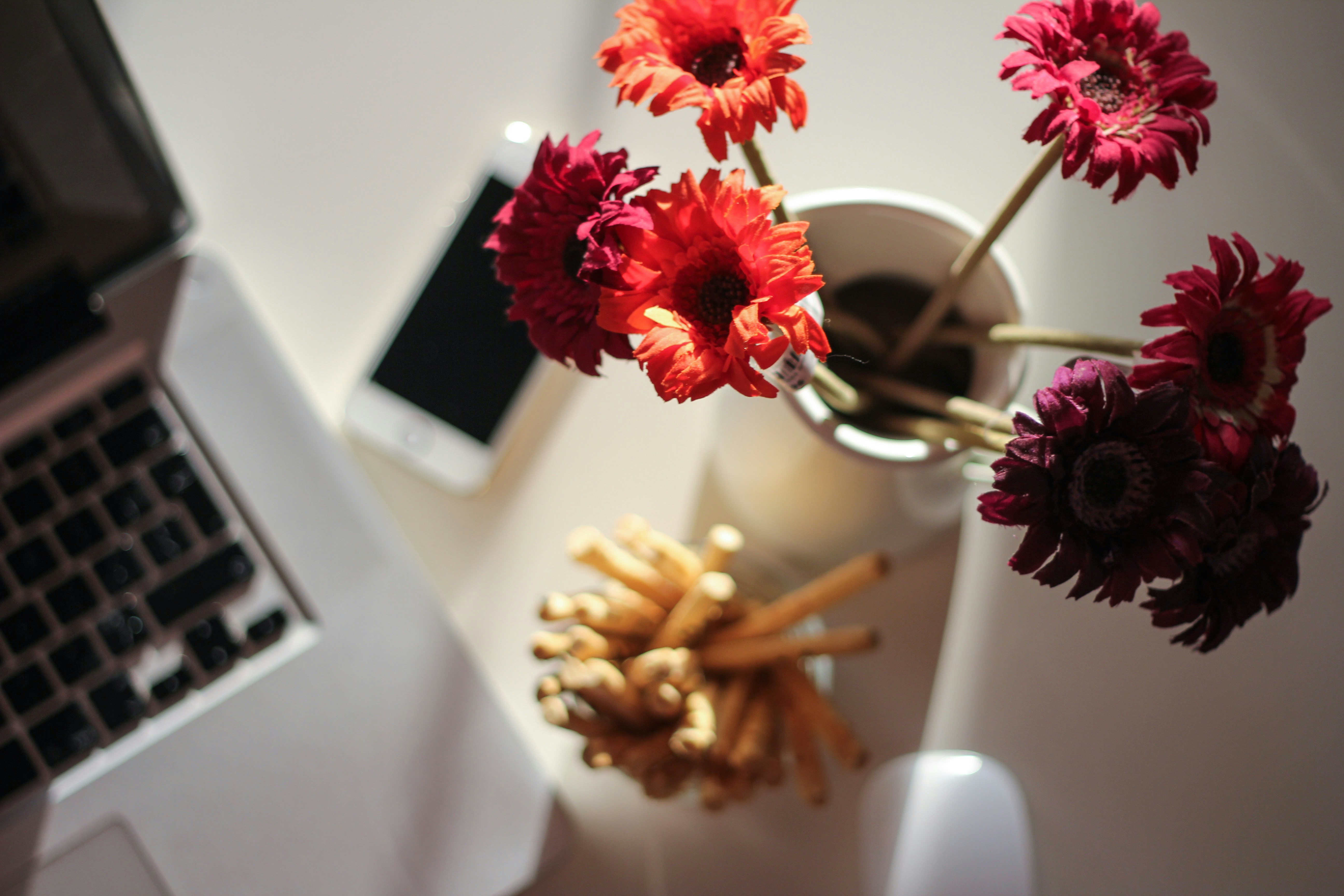 Crimson Florals Over a Soft Desk: A Top-Down Still Life