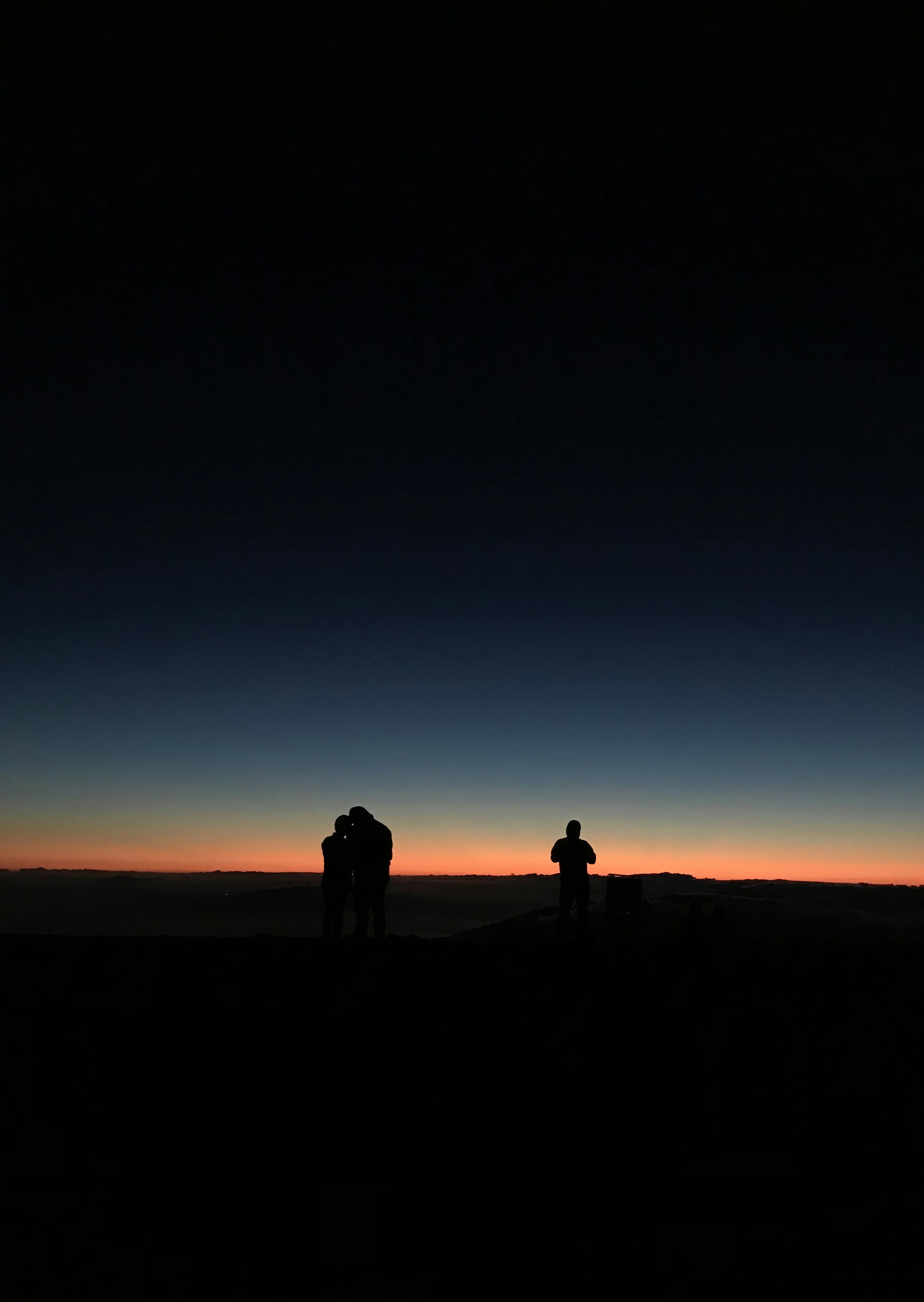 Three Silhouettes at Dusk on a Glowing Horizon