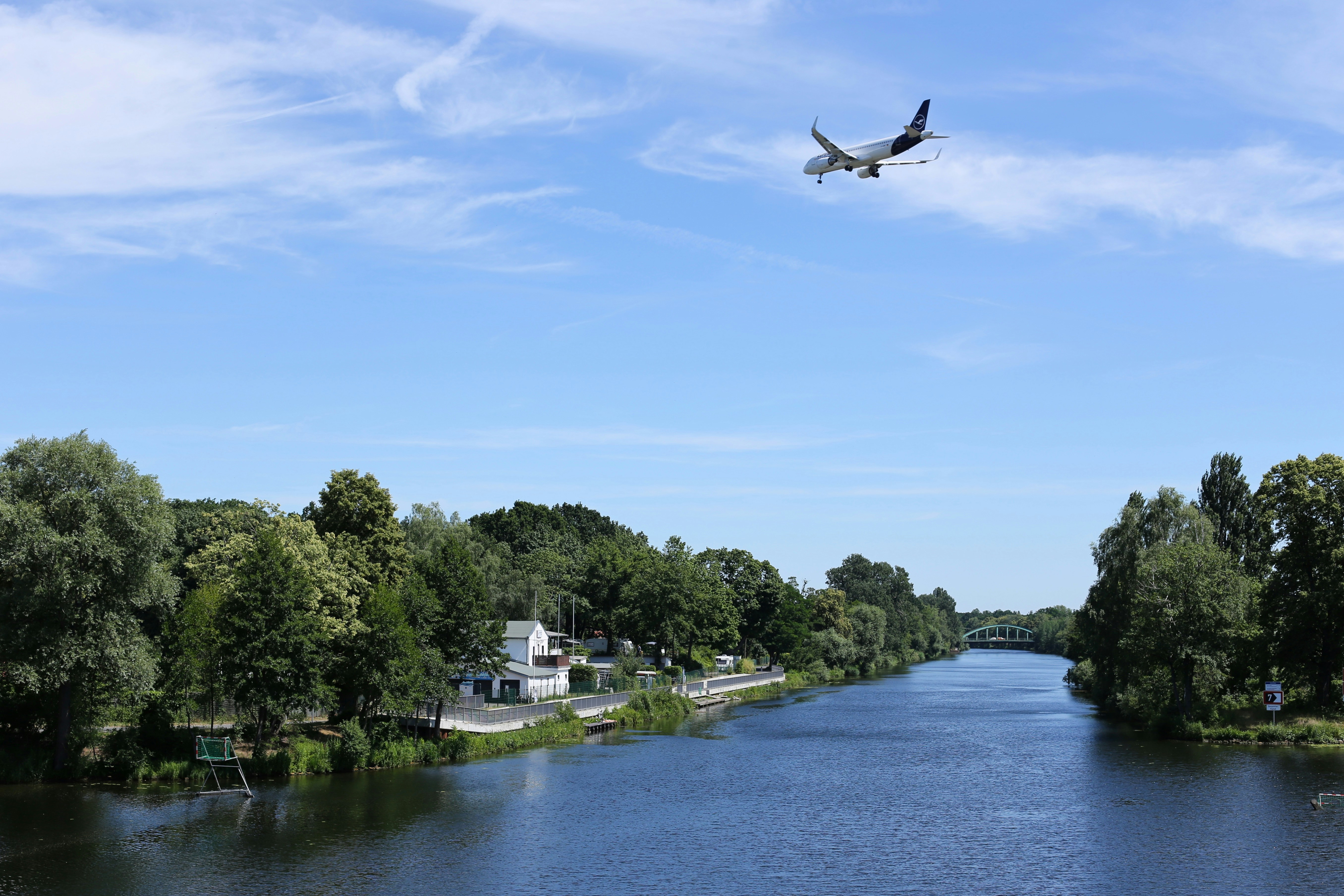 a plane flying over a river with houses and trees