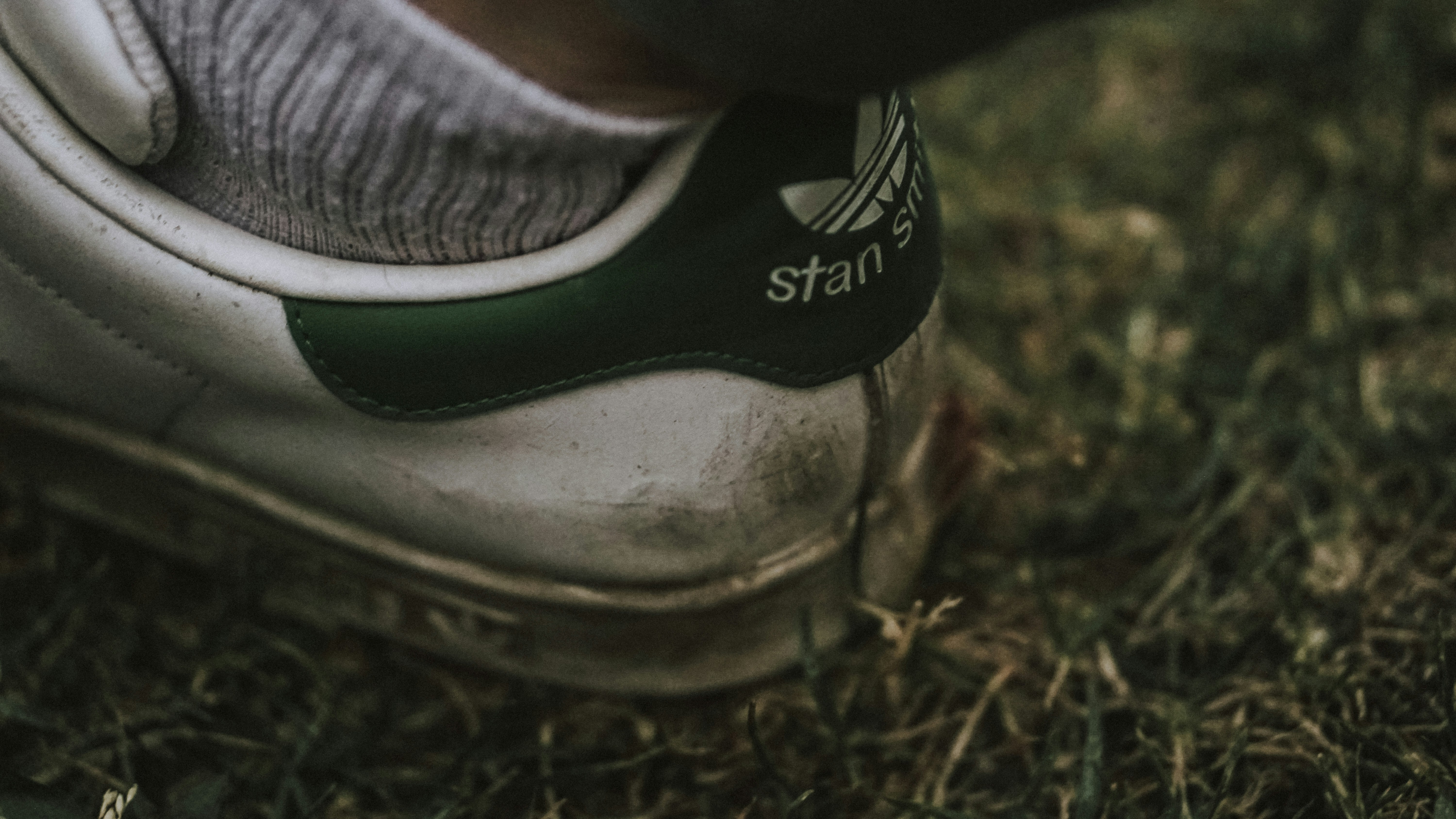 unpaired white and green Adidas Stand Smith slow-top sneaker