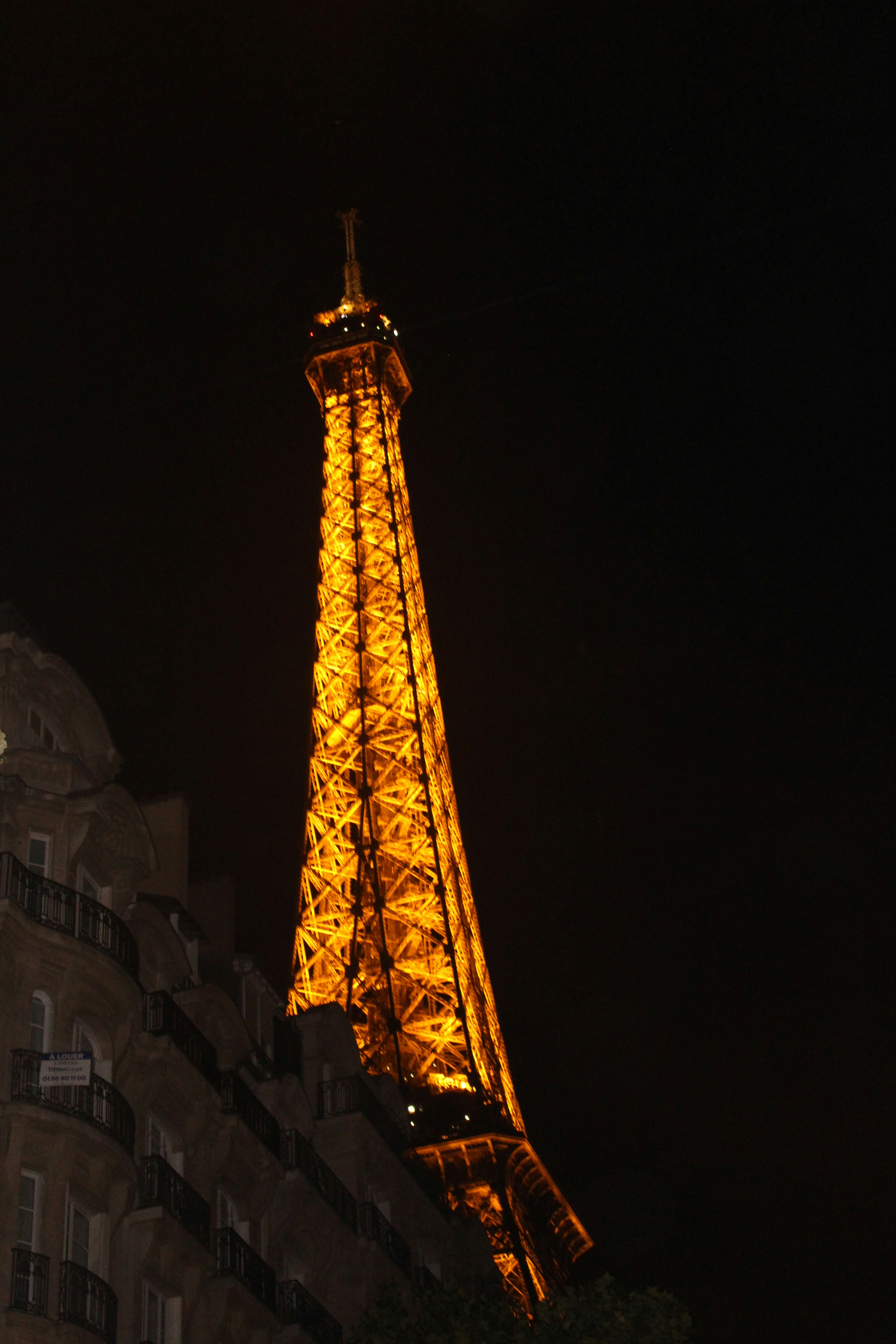 Golden Torch: nocturnal silhouette of the Eiffel-like tower piercing the Parisian night