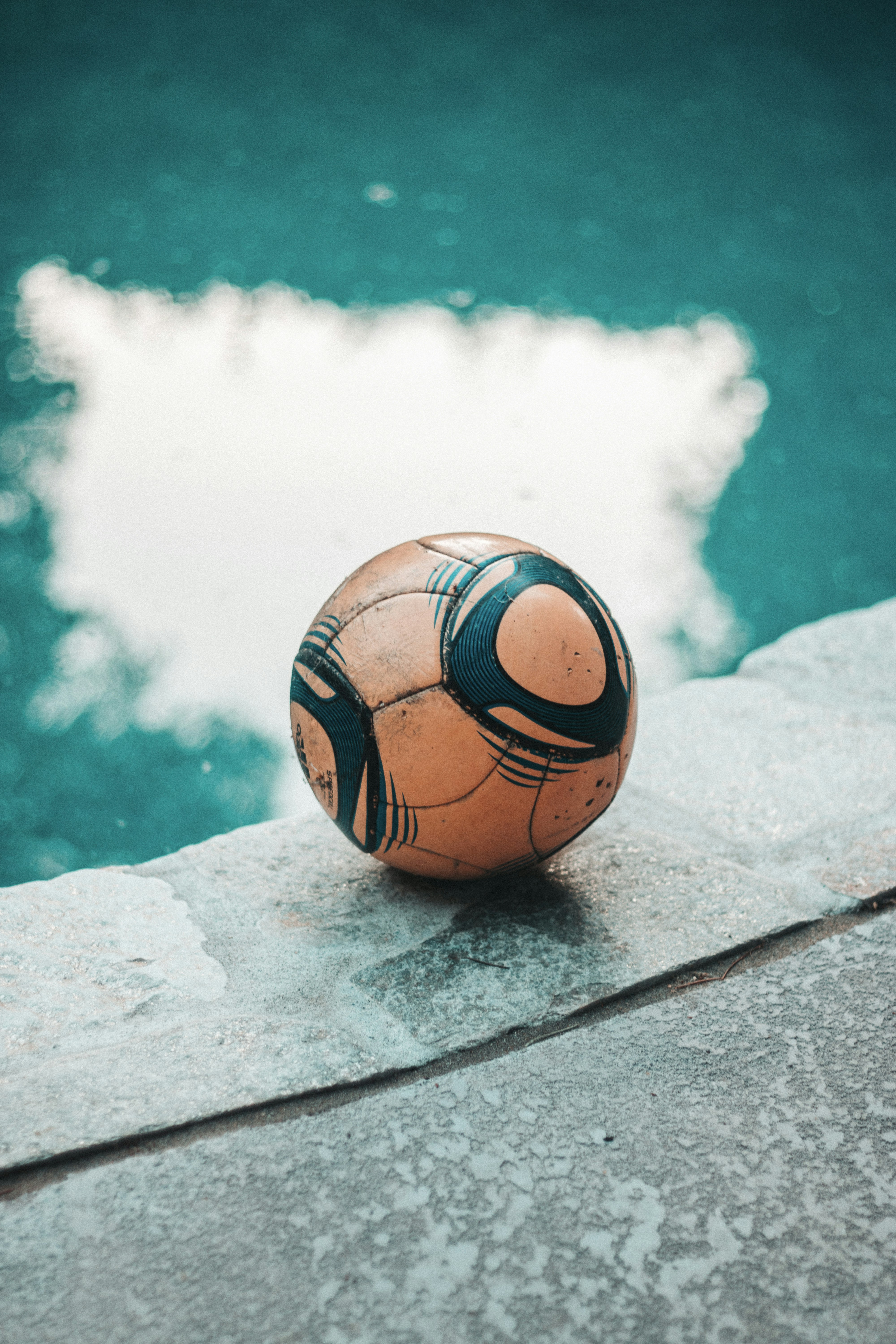 Orange Ceramic Orb Perched on a Weathered Ledge Over Turquoise Water