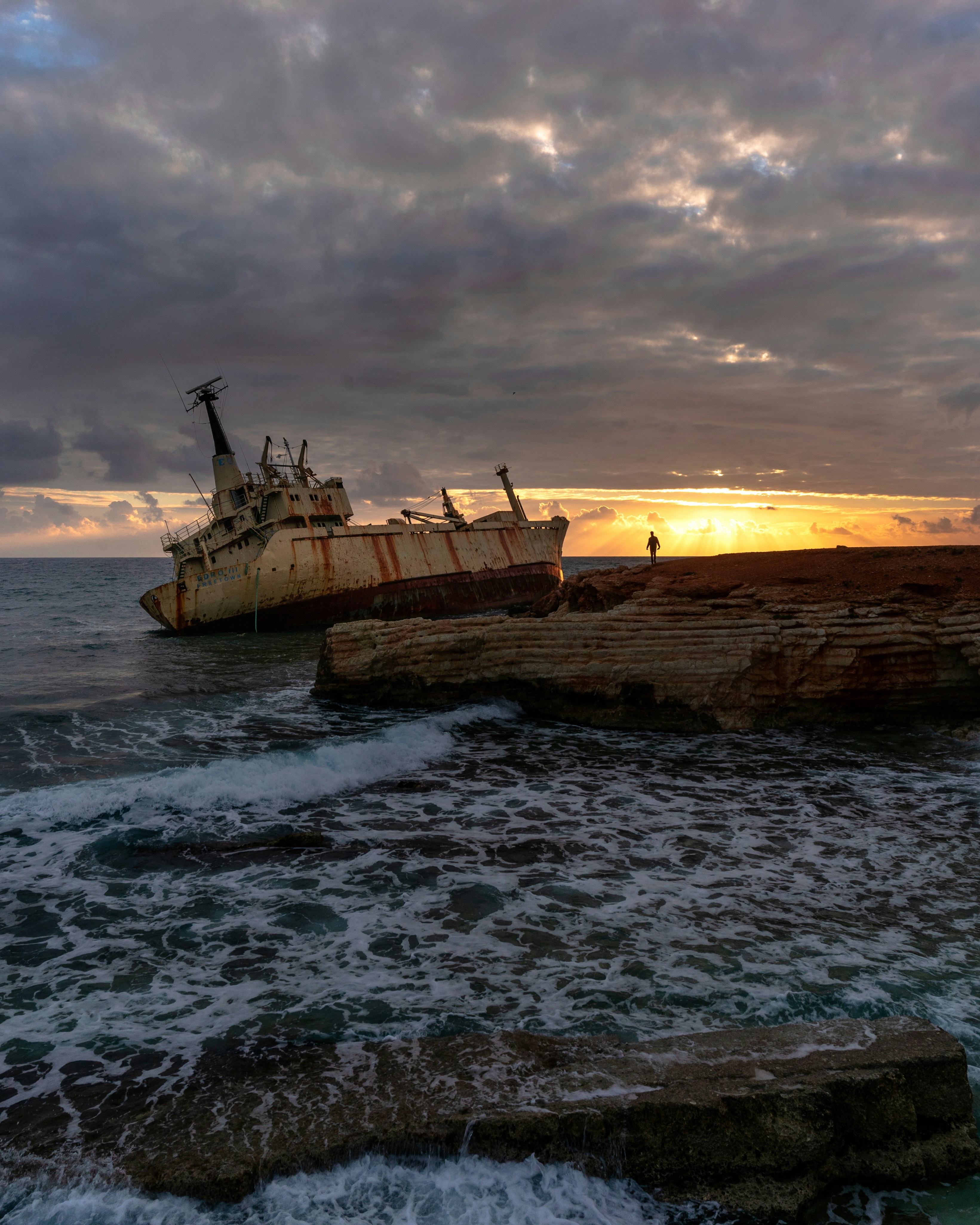 Sunset Sentinel: A Rusted Shipwreck Resting on Tidal Ridges