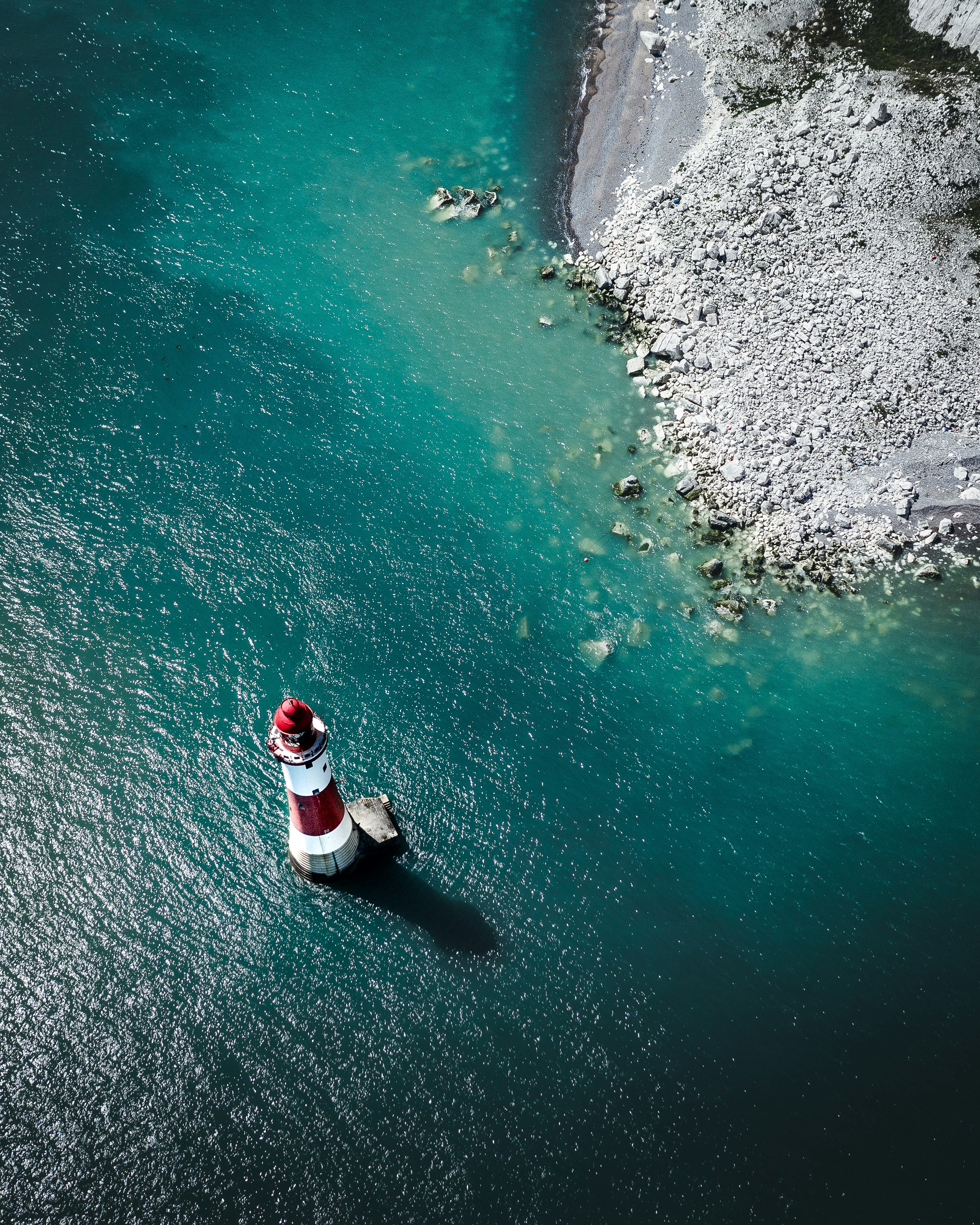 Lighthouse Sentinel: Red and White Tower Anchored in Emerald Waters
