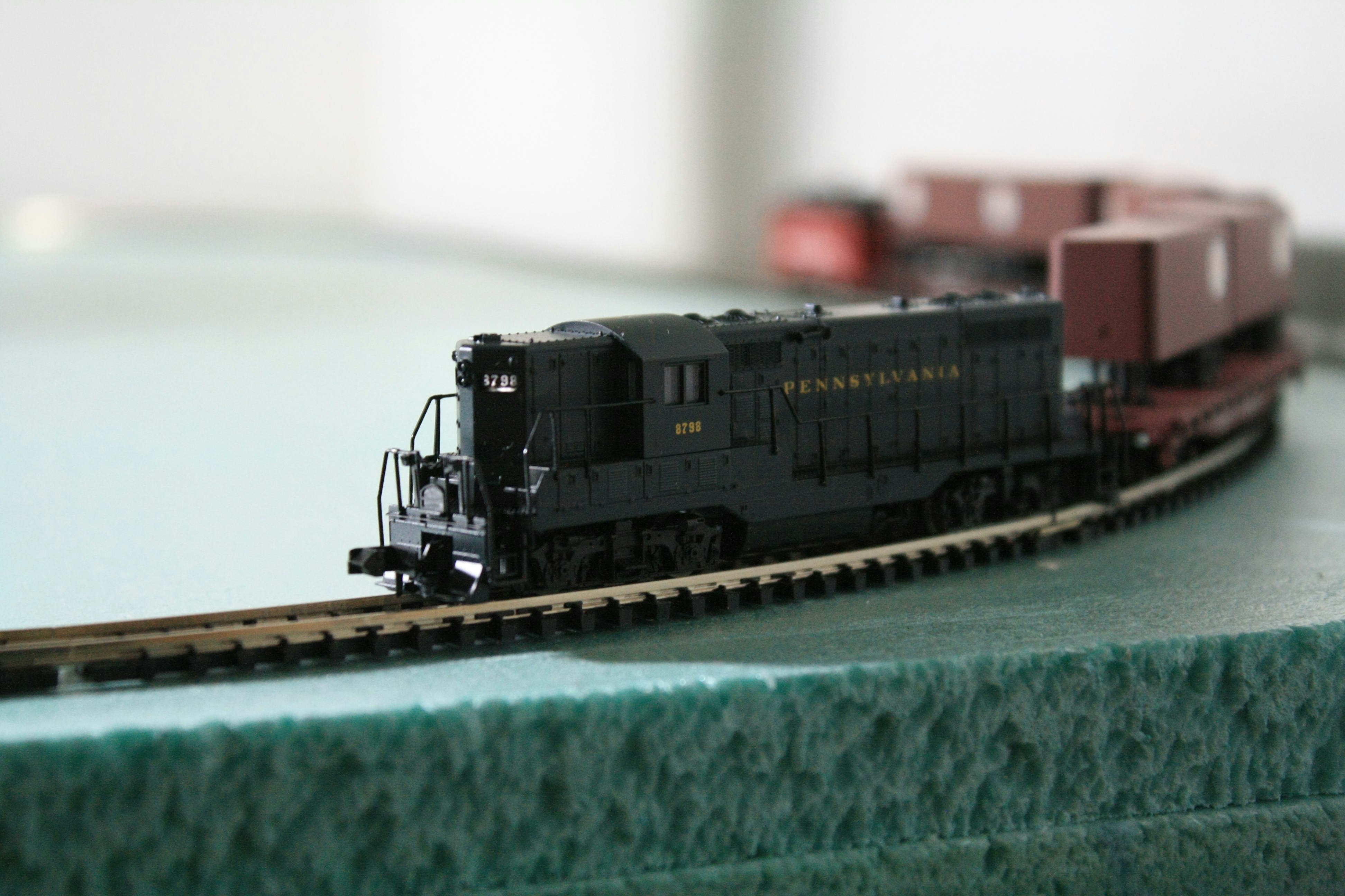 A detailed model train engine navigating a curved track, showcasing intricate design and craftsmanship. The scene captures the essence of model railroading.