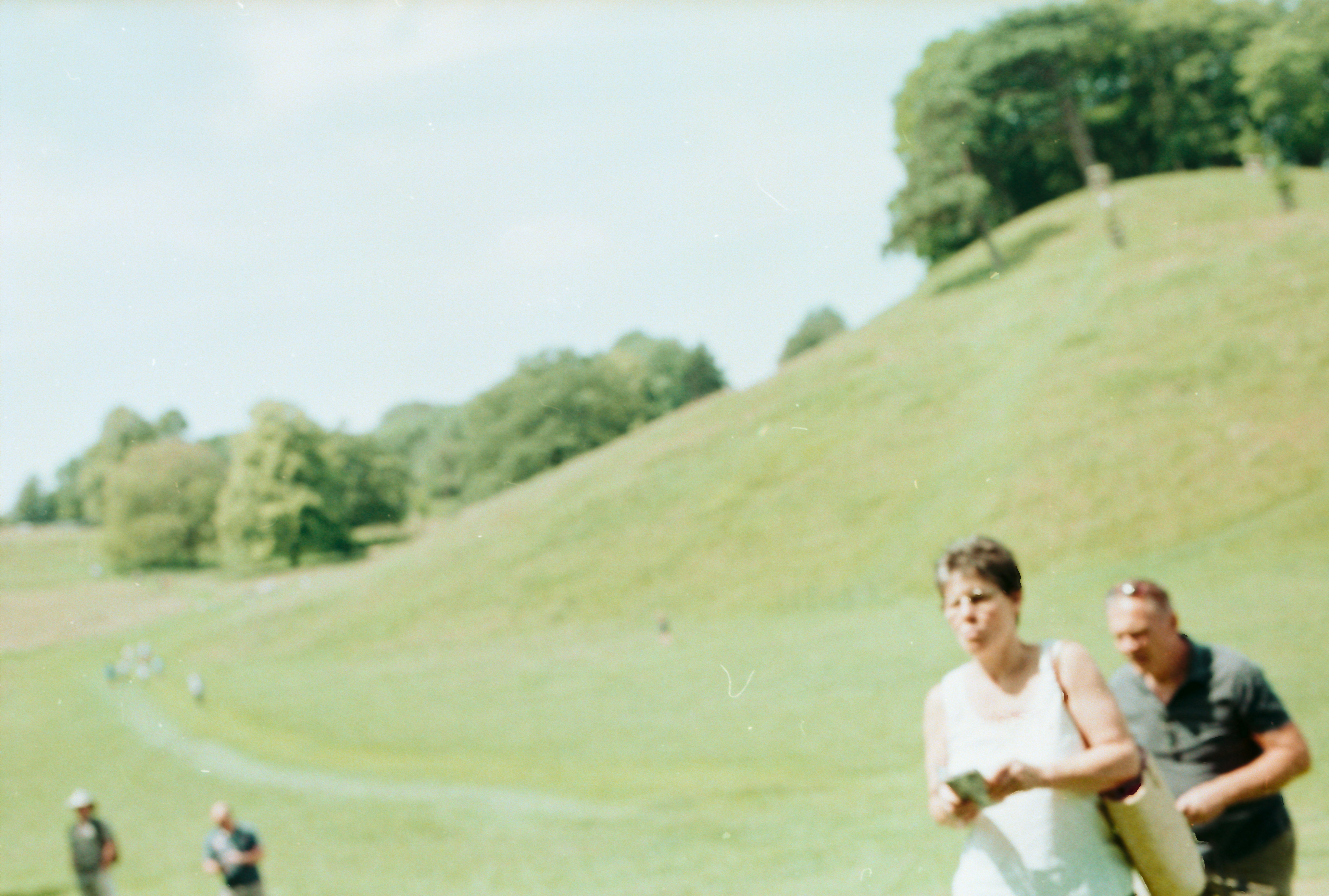 Two runners crest a sunlit hill in a breezy park