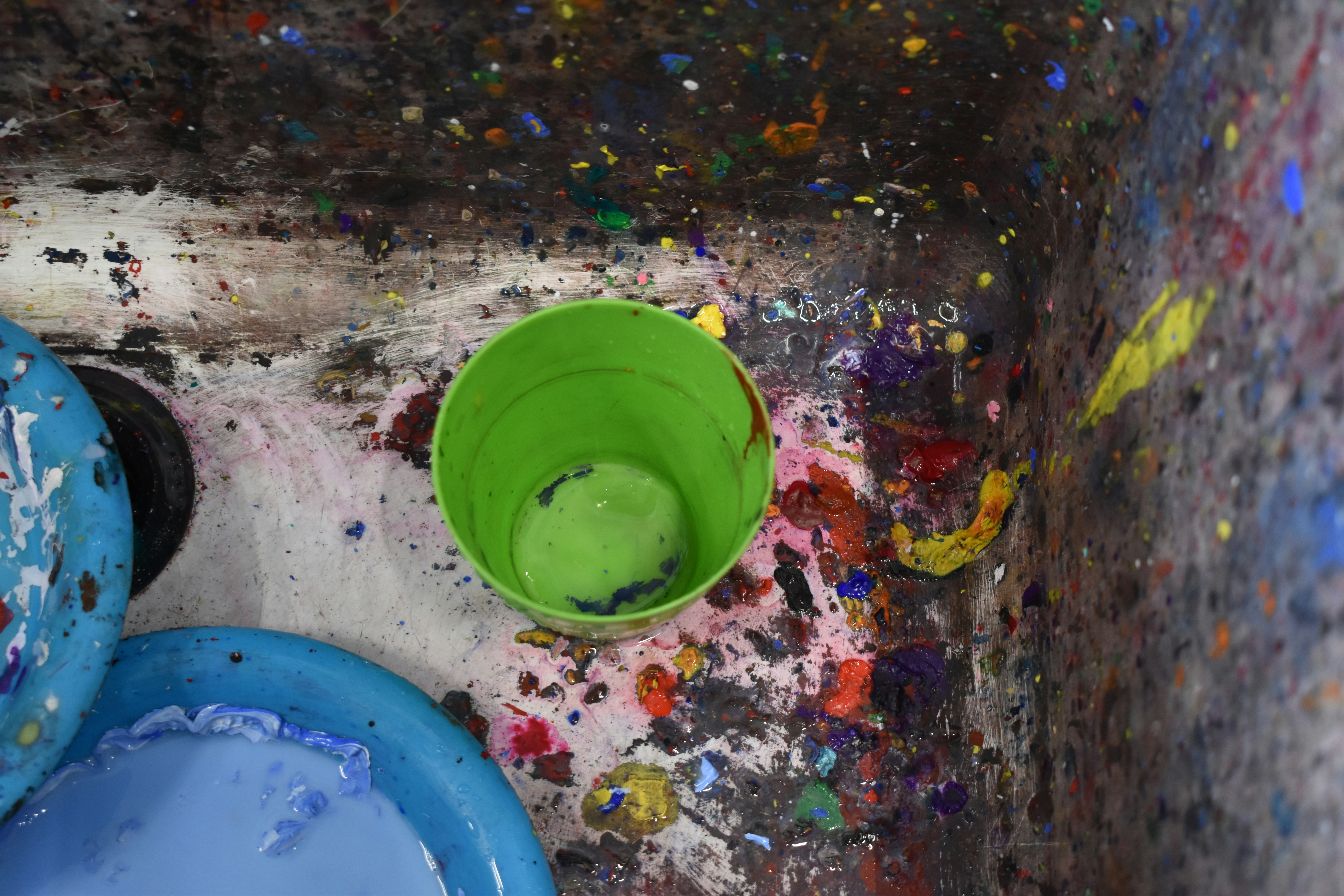 Green Cup in a Color-Splashed Studio: An Overhead Study of Paint and Texture
