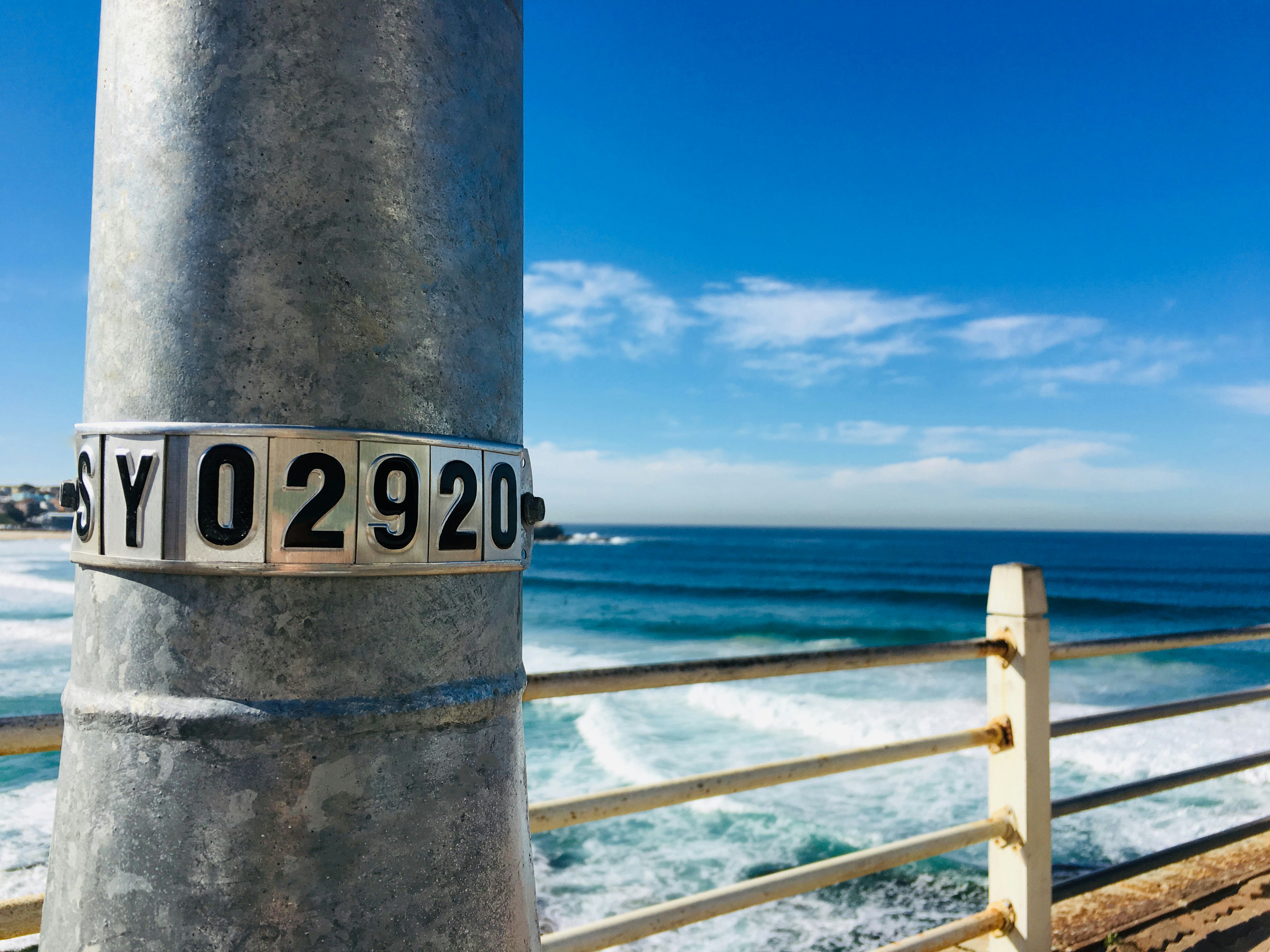 Coastal Post: Distant Waves Meet a Weathered Pier Rail