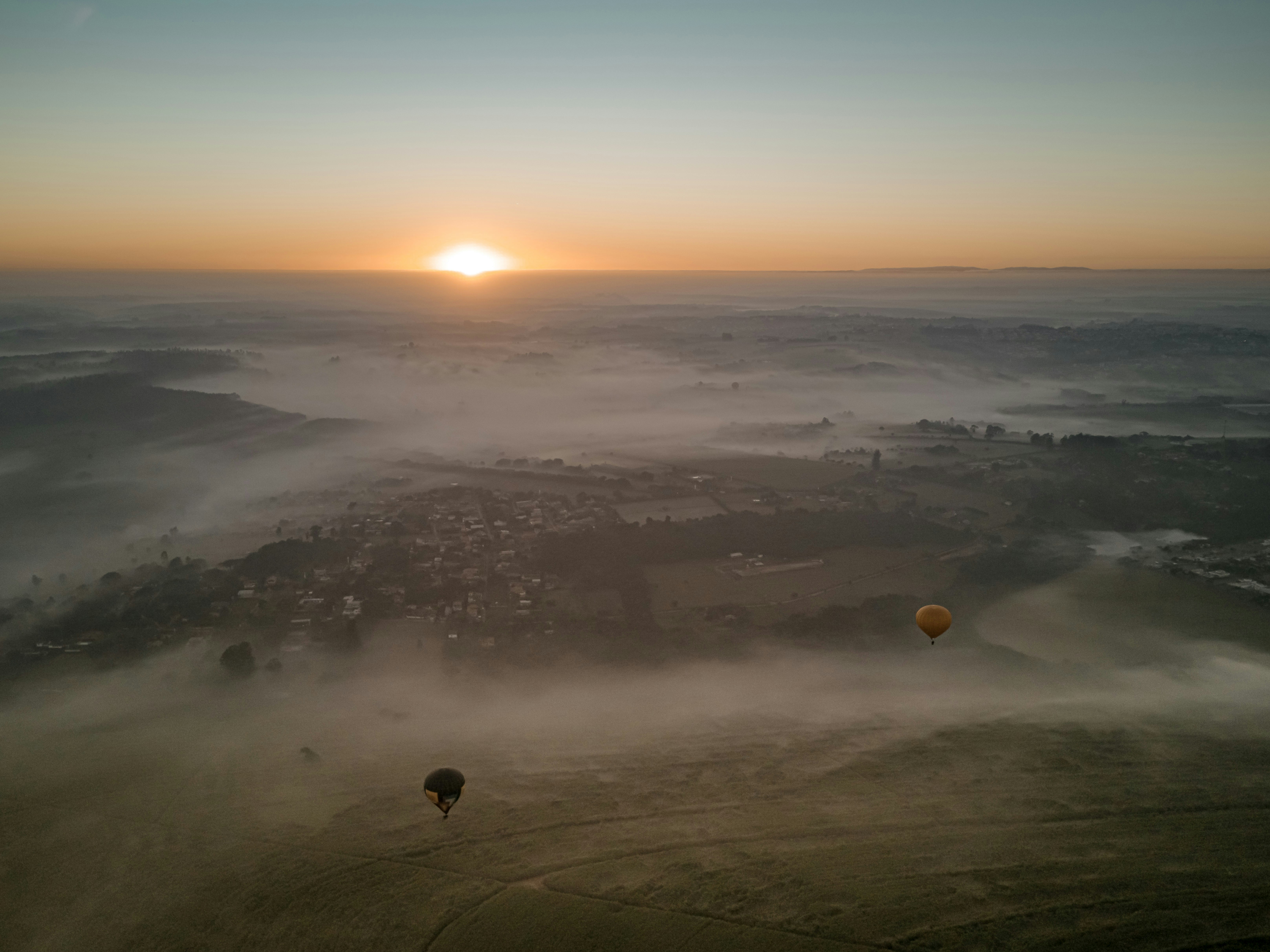 Sunrise over a misty valley with drifting balloons