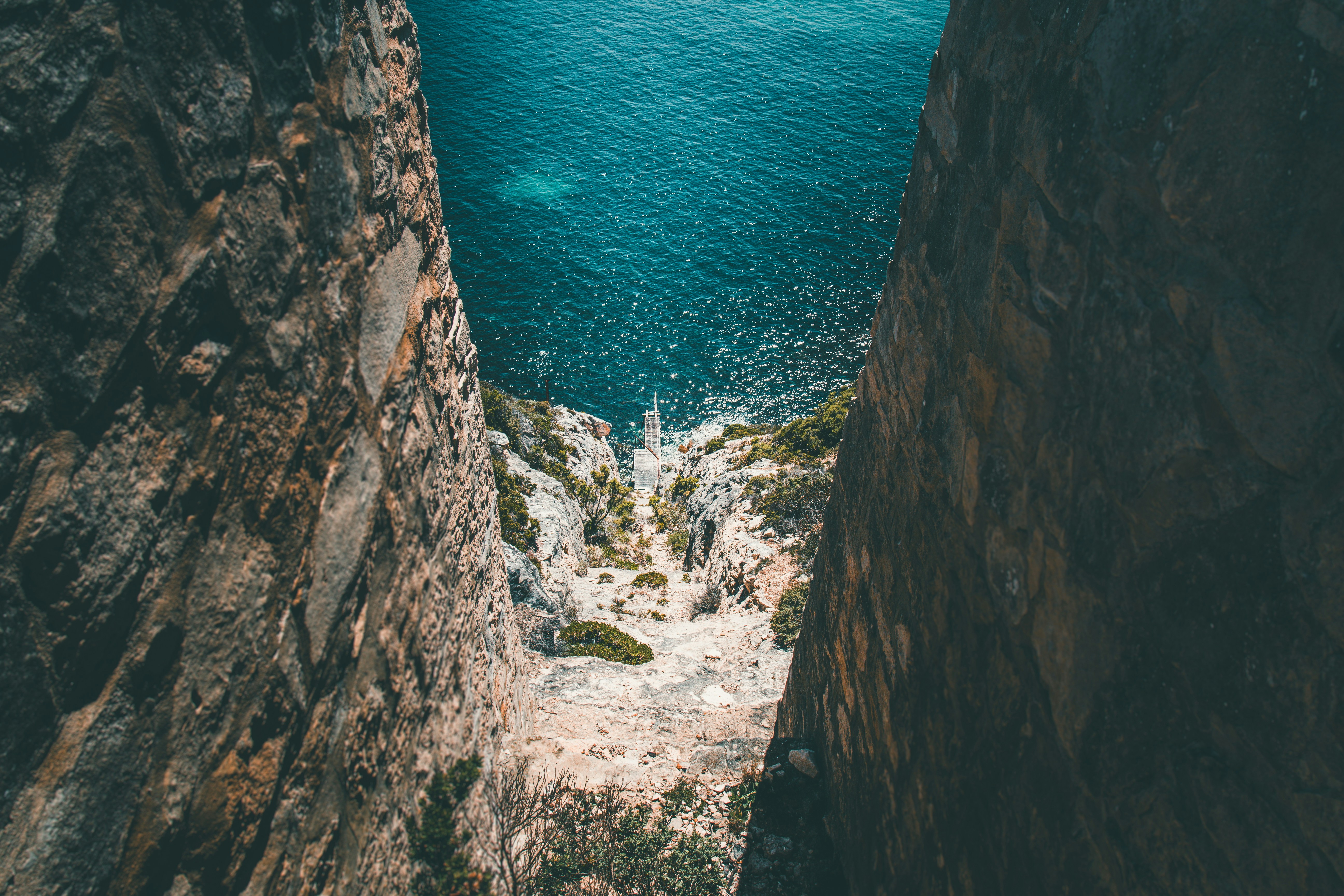 Chasm Gate to the Sea: A Narrow Cliff Passage Framing Turquoise Horizon