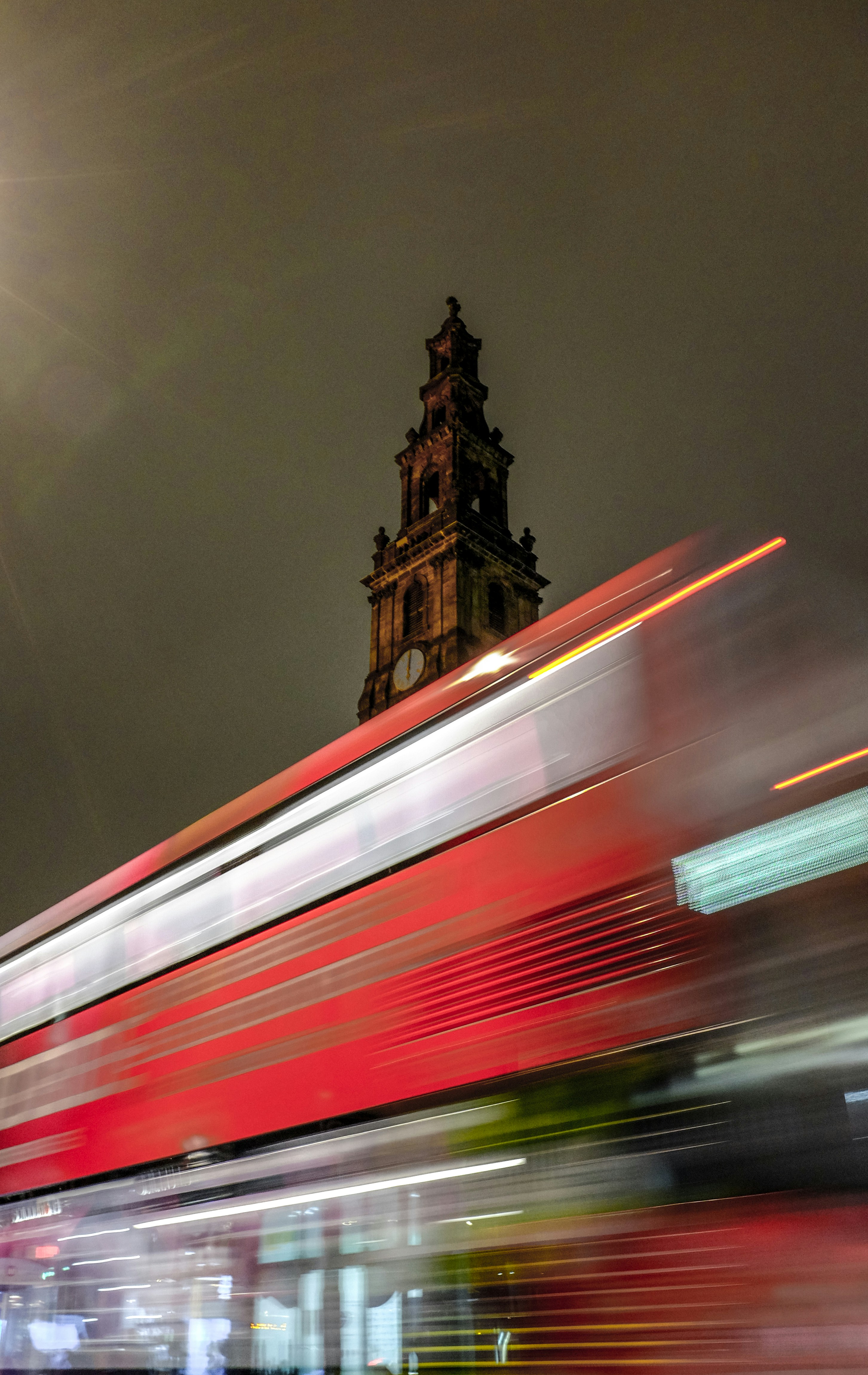 Tower Clock Silhouette Amidst Blurred Red Transit